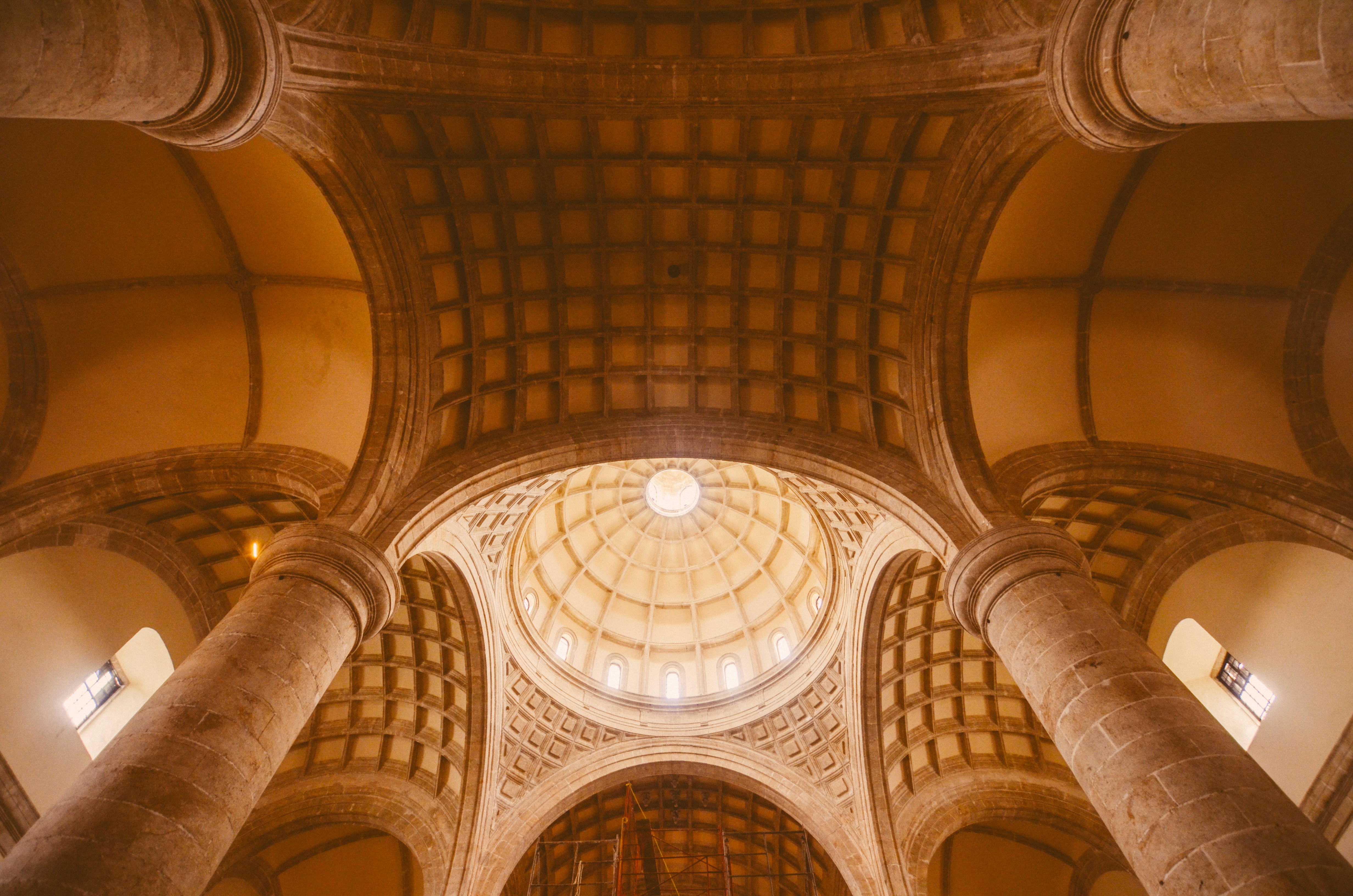 Grand stone columns support an intricately patterned dome ceiling in a spacious hall.
