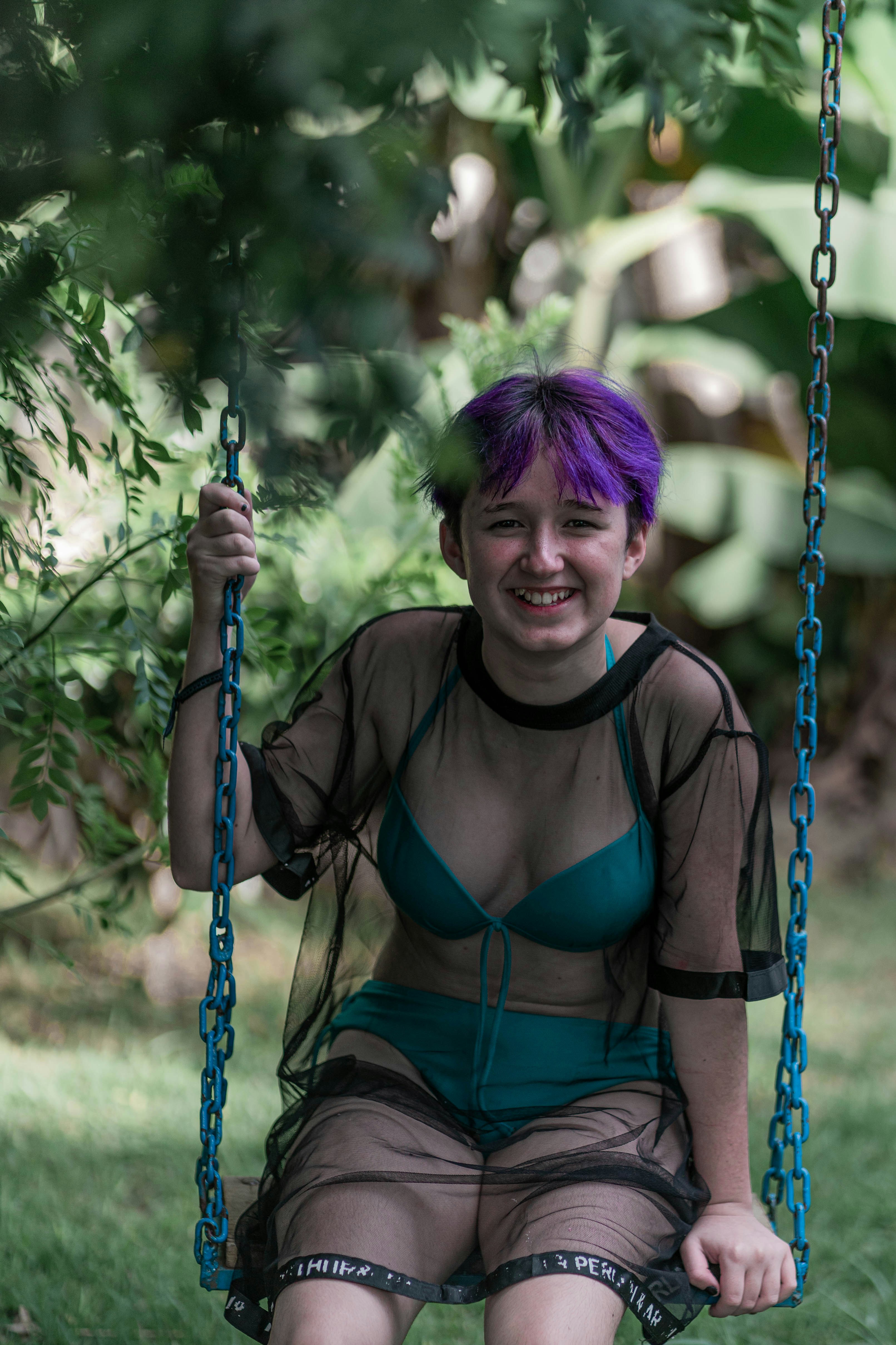 a woman with purple hair sitting on a swing