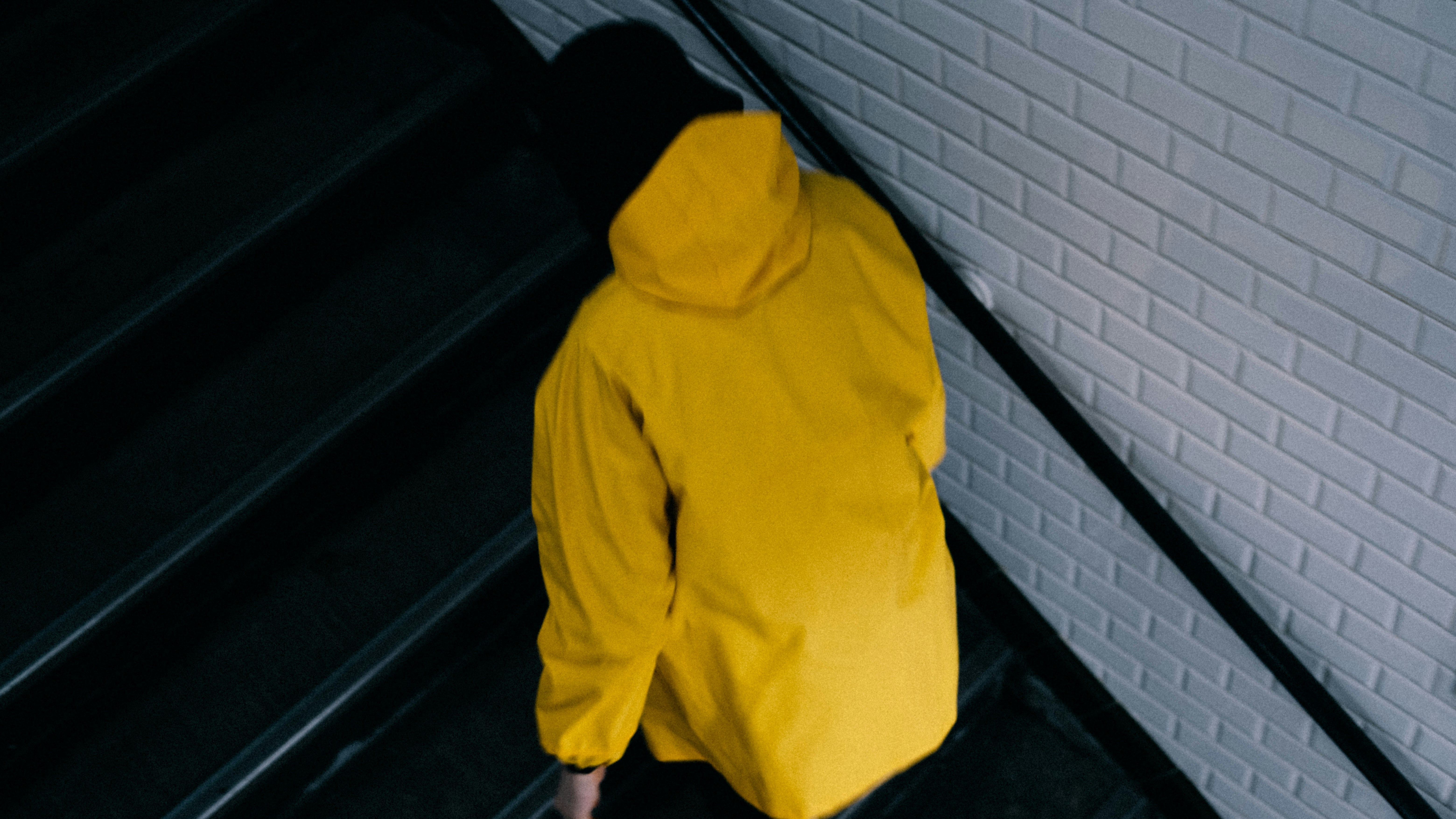 Una persona con un impermeable amarillo subiendo un tramo de escaleras ...