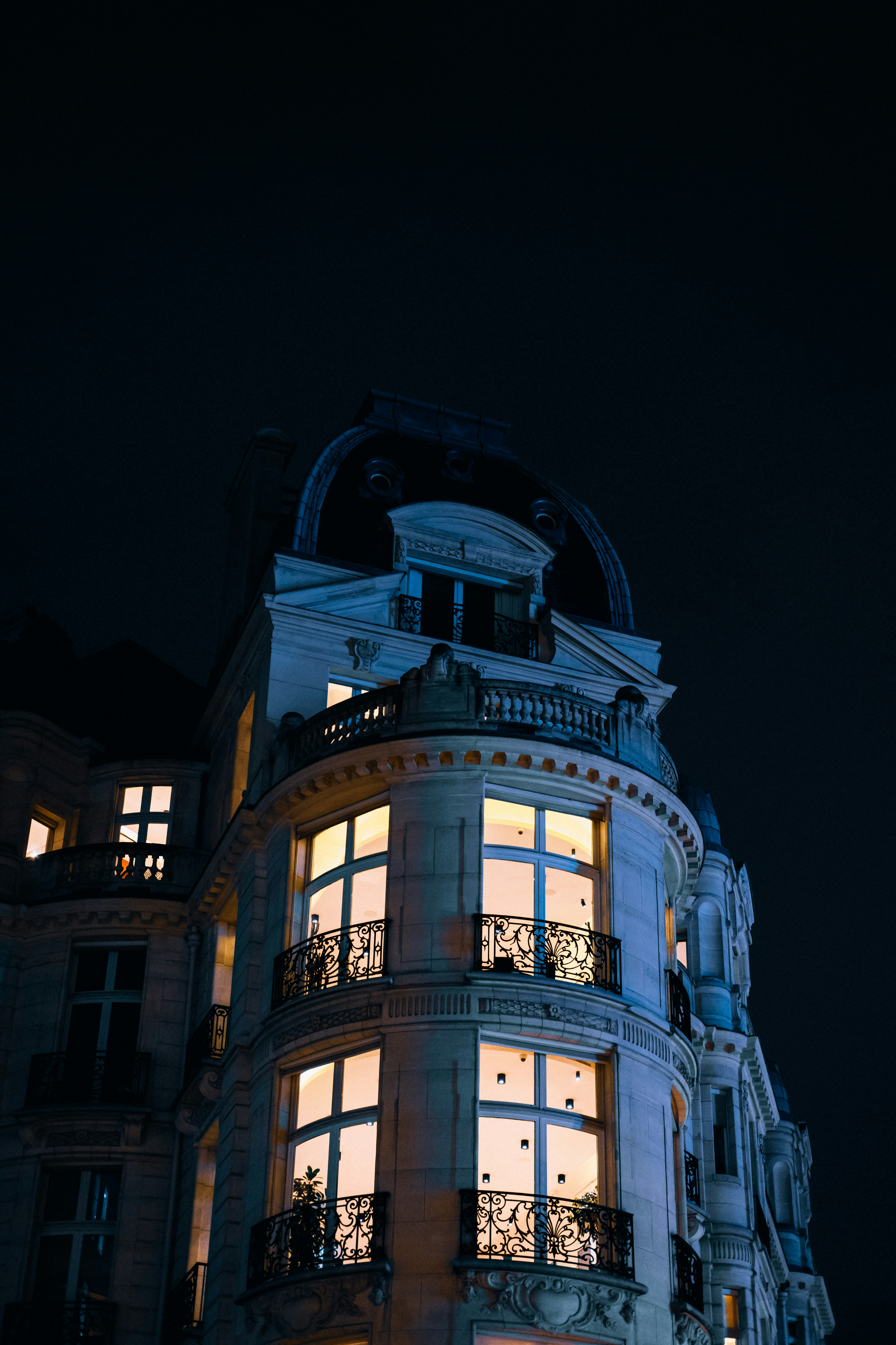 Nocturnal Beaux-Arts Corner: Warm Bay Windows on a Deep Blue Facade