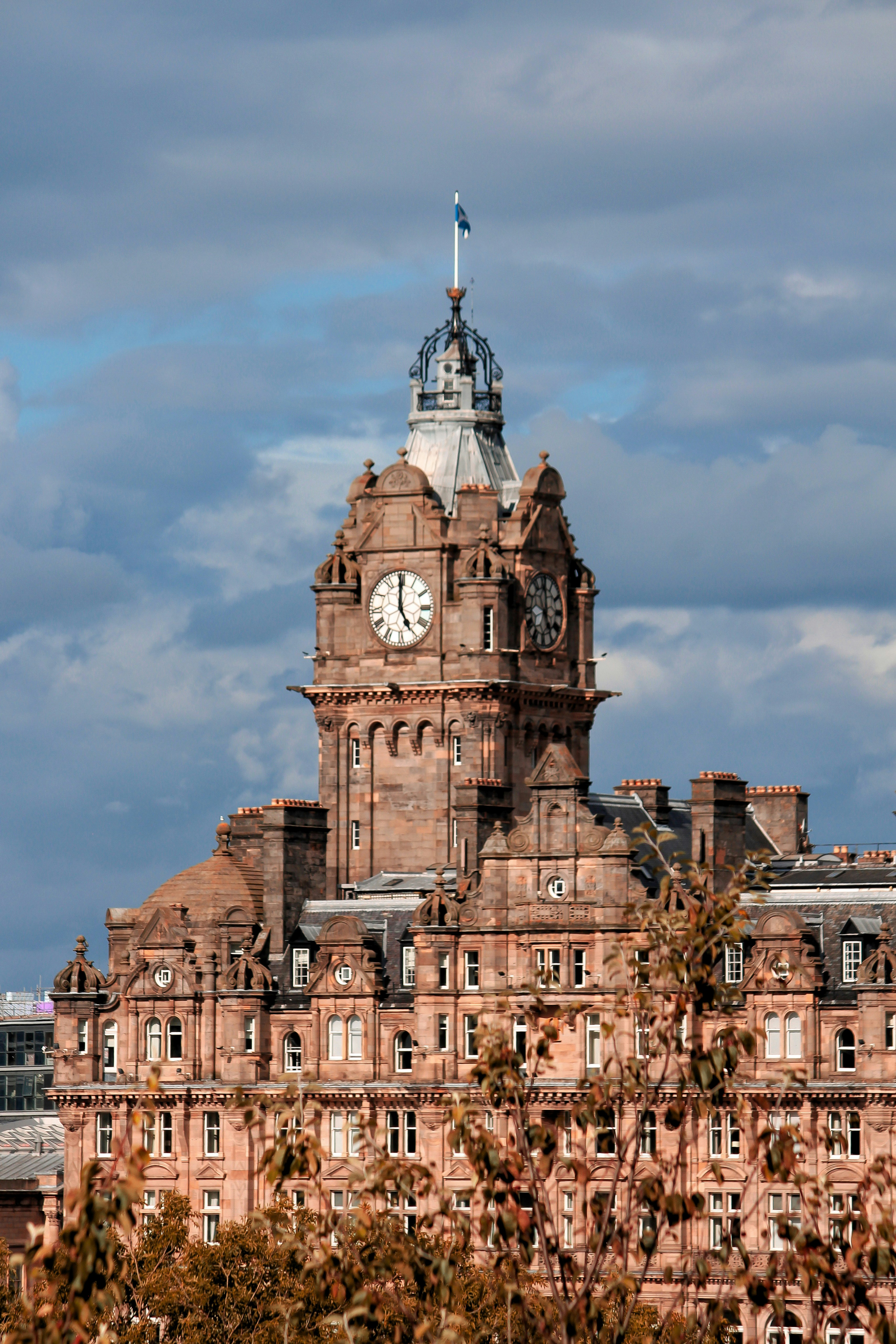 Historic clock tower adorned with intricate architectural details against a backdrop of dramatic clouds.