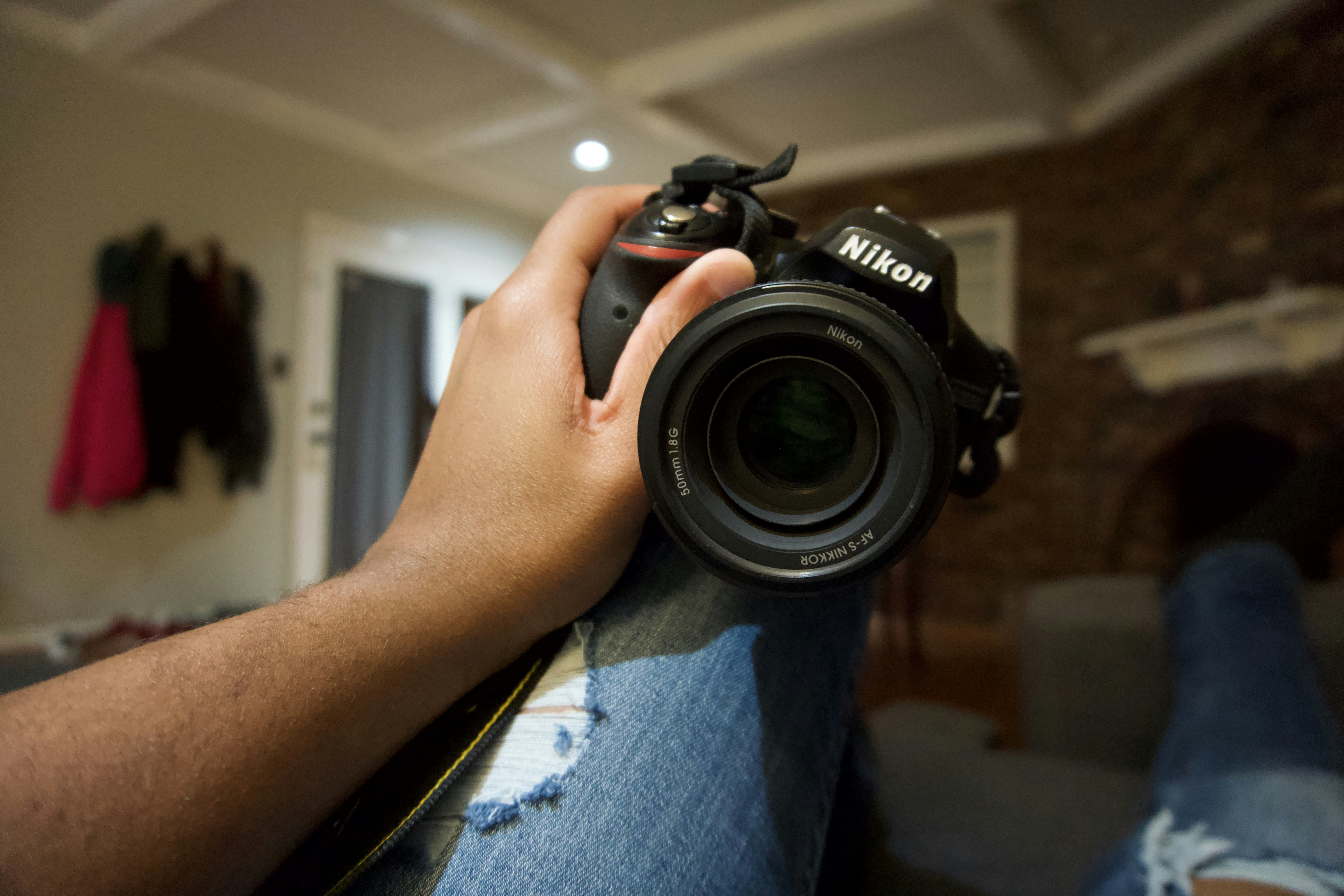 Person holding a DSLR camera indoors, capturing a relaxed home setting.