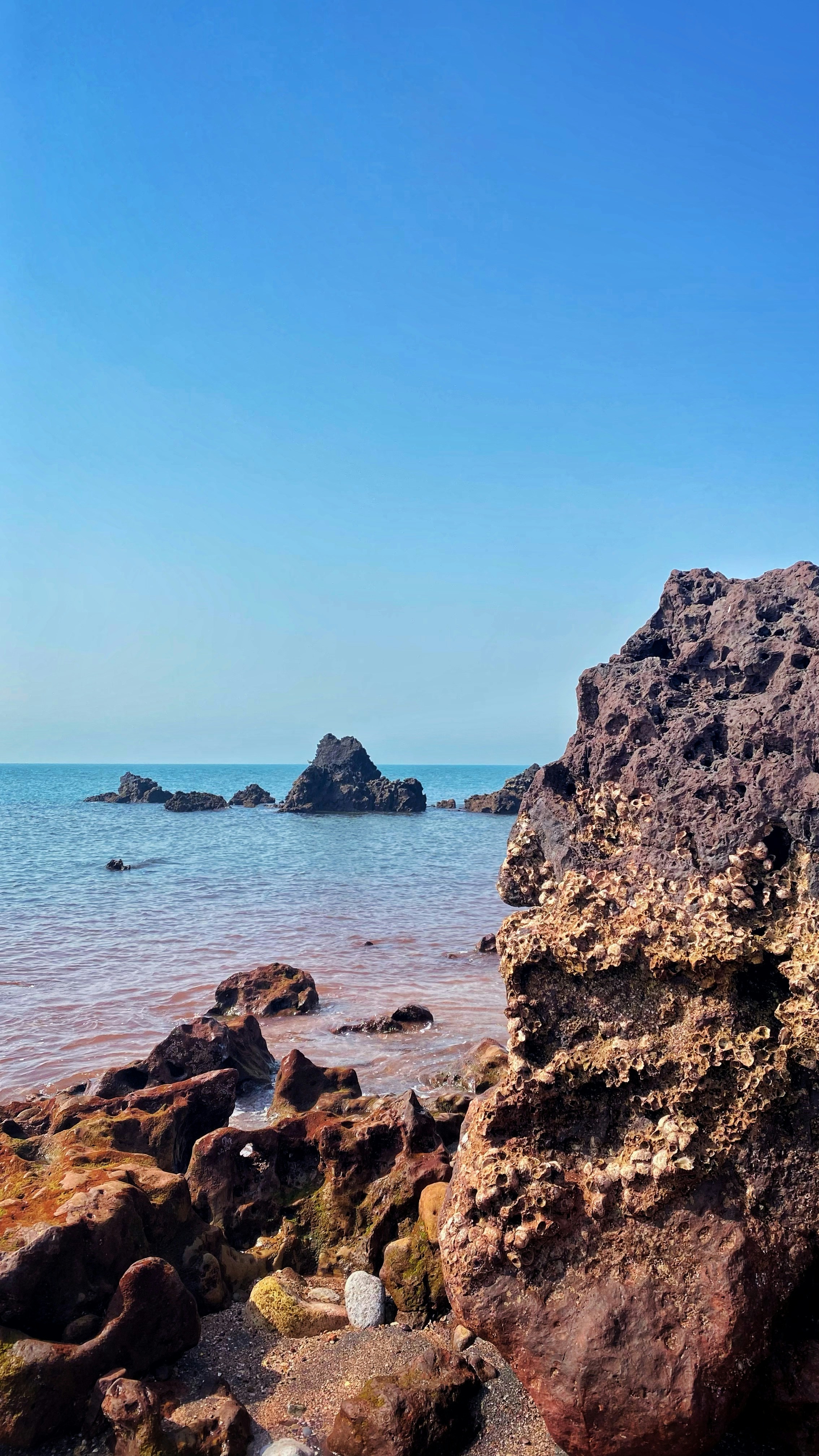 A large rock sitting on top of a beach next to the ocean photo – Free ...