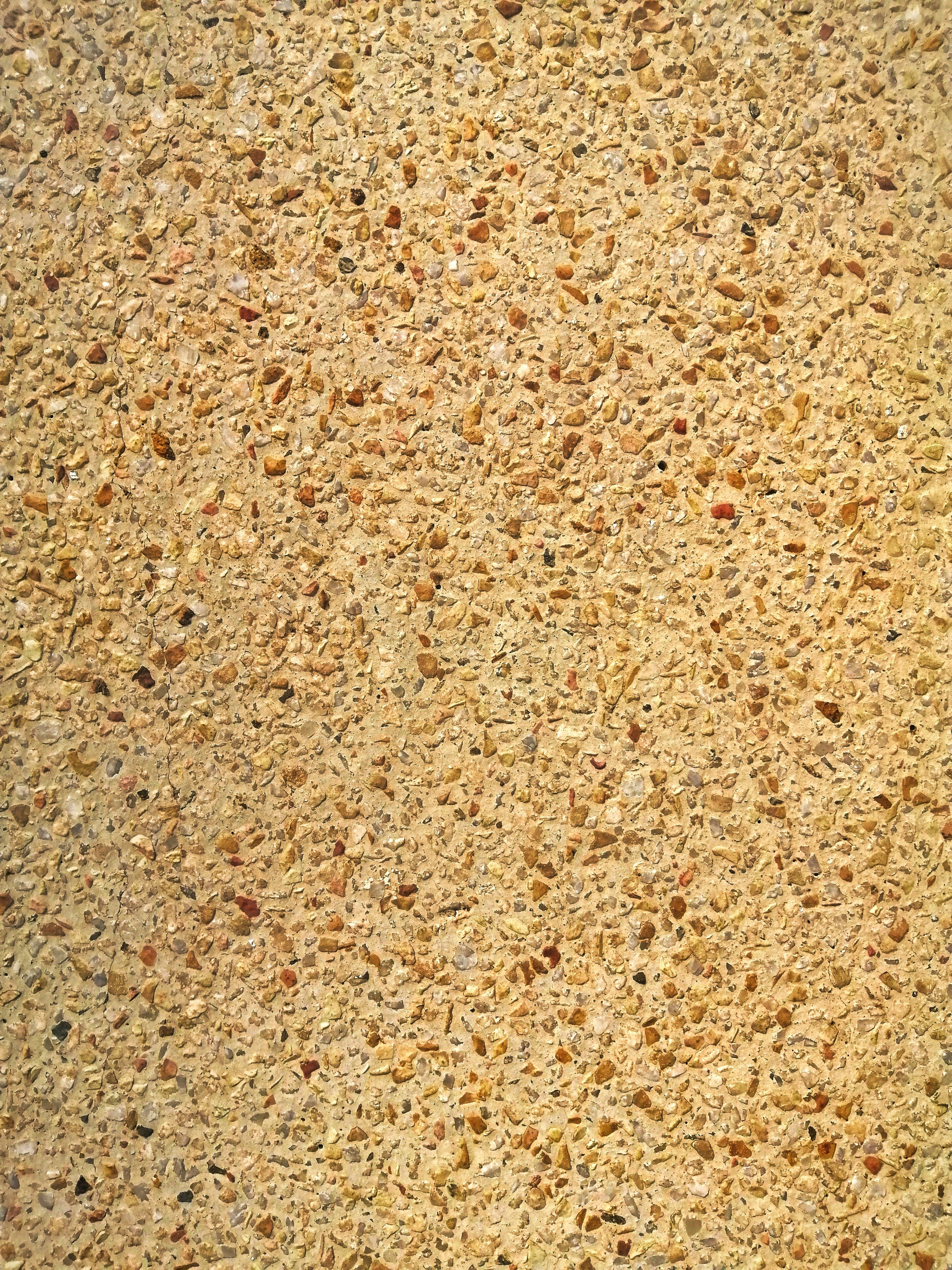 Close-up of a textured surface showcasing a blend of earthy tones and small stones. The intricate patterns highlight natural materials and craftsmanship.