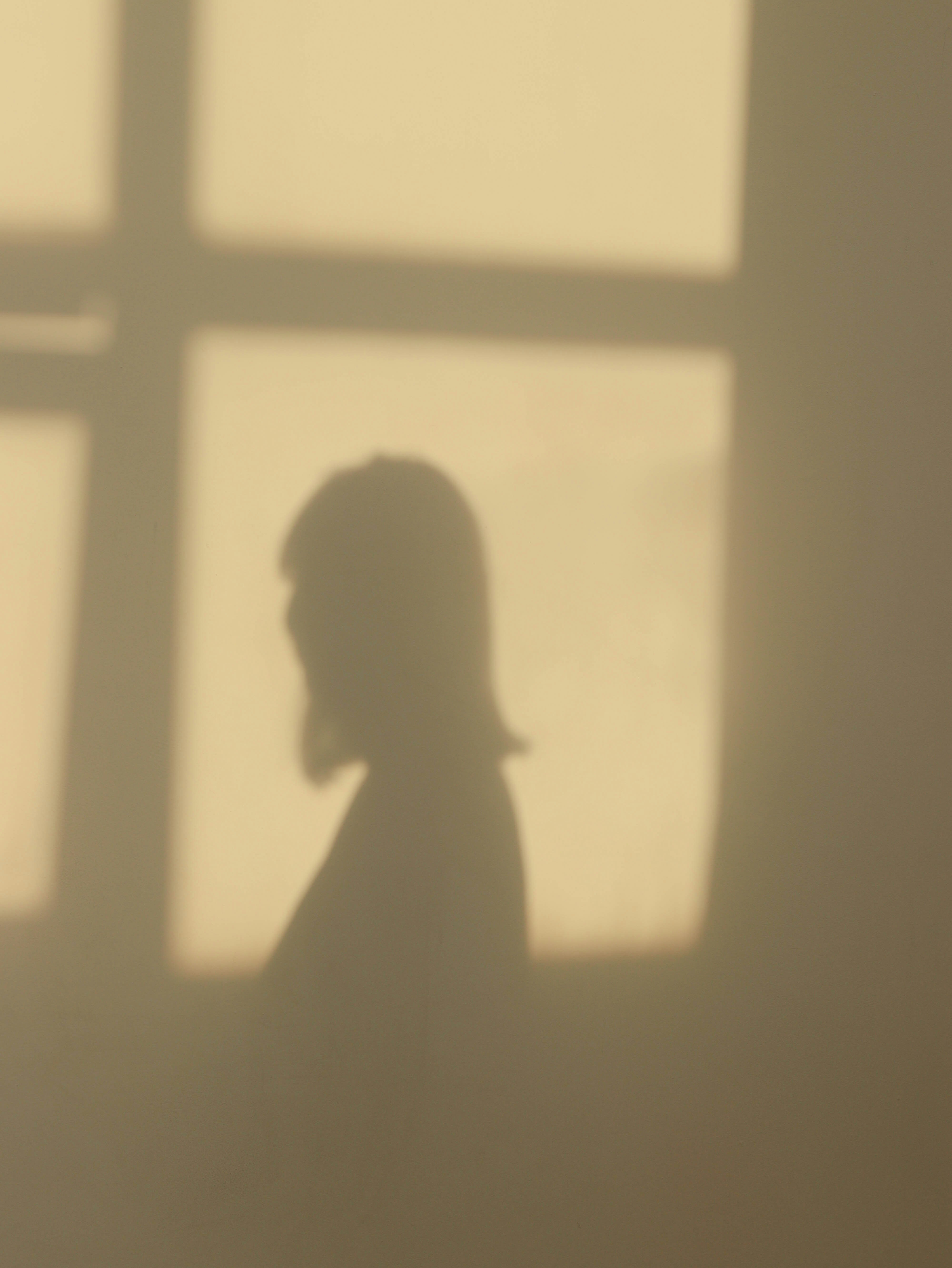 Silhouette of a person against a softly illuminated background, evoking a sense of introspection. The warm tones create a tranquil atmosphere.