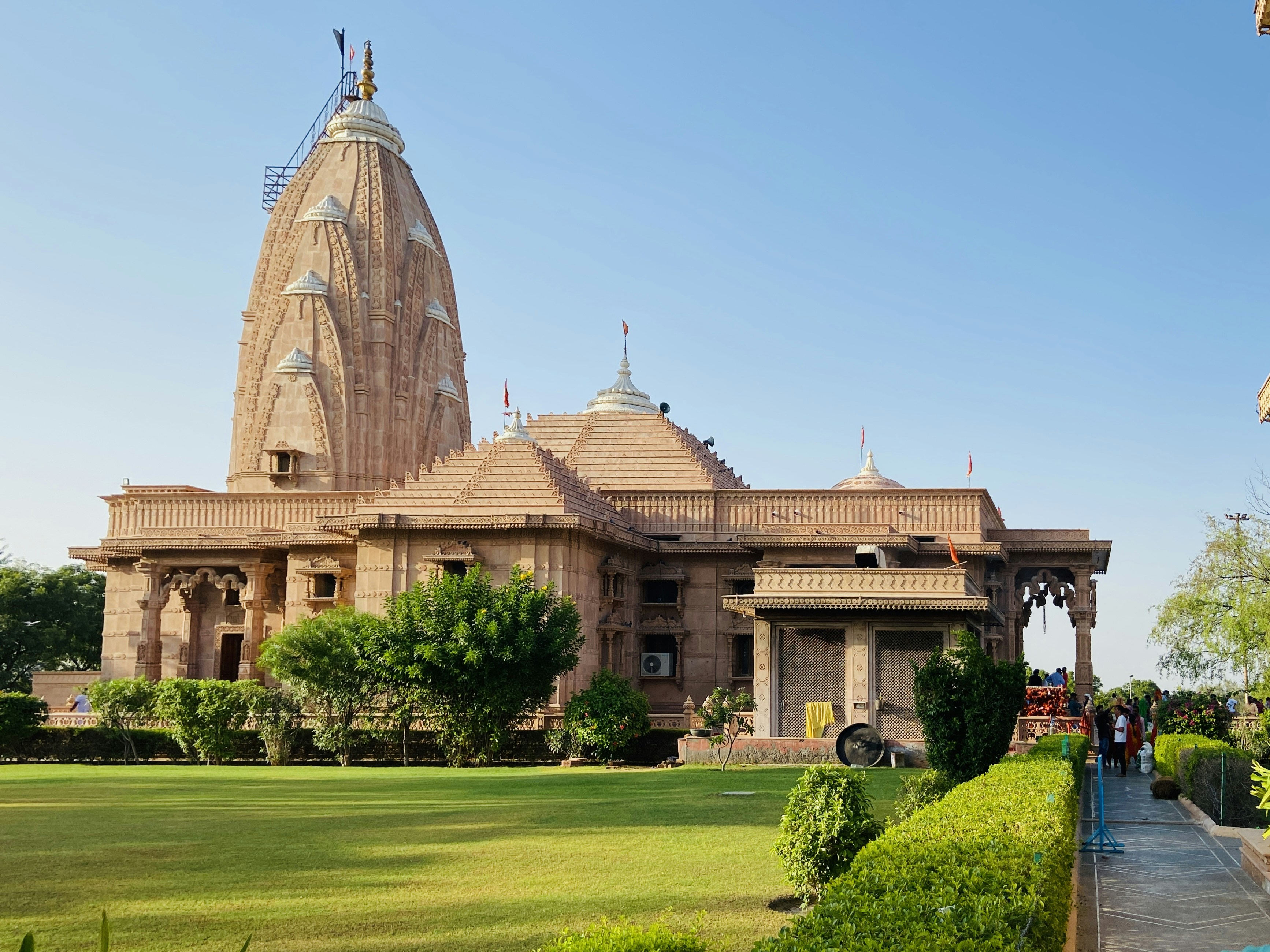 A large building with a tall tower next to a lush green field photo ...