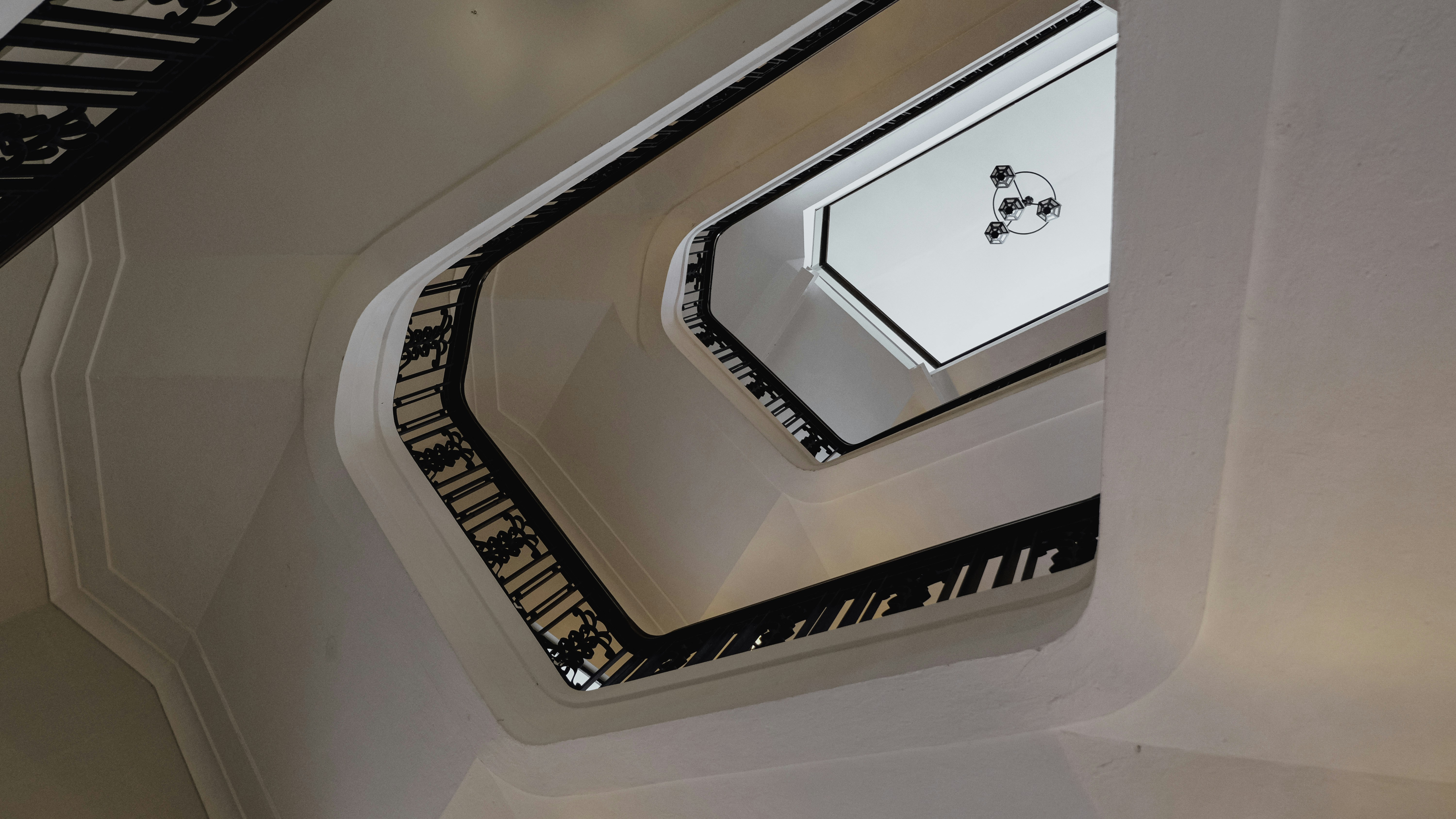 Intricate stairwell with elegant railings and a skylight, showcasing architectural symmetry and design.