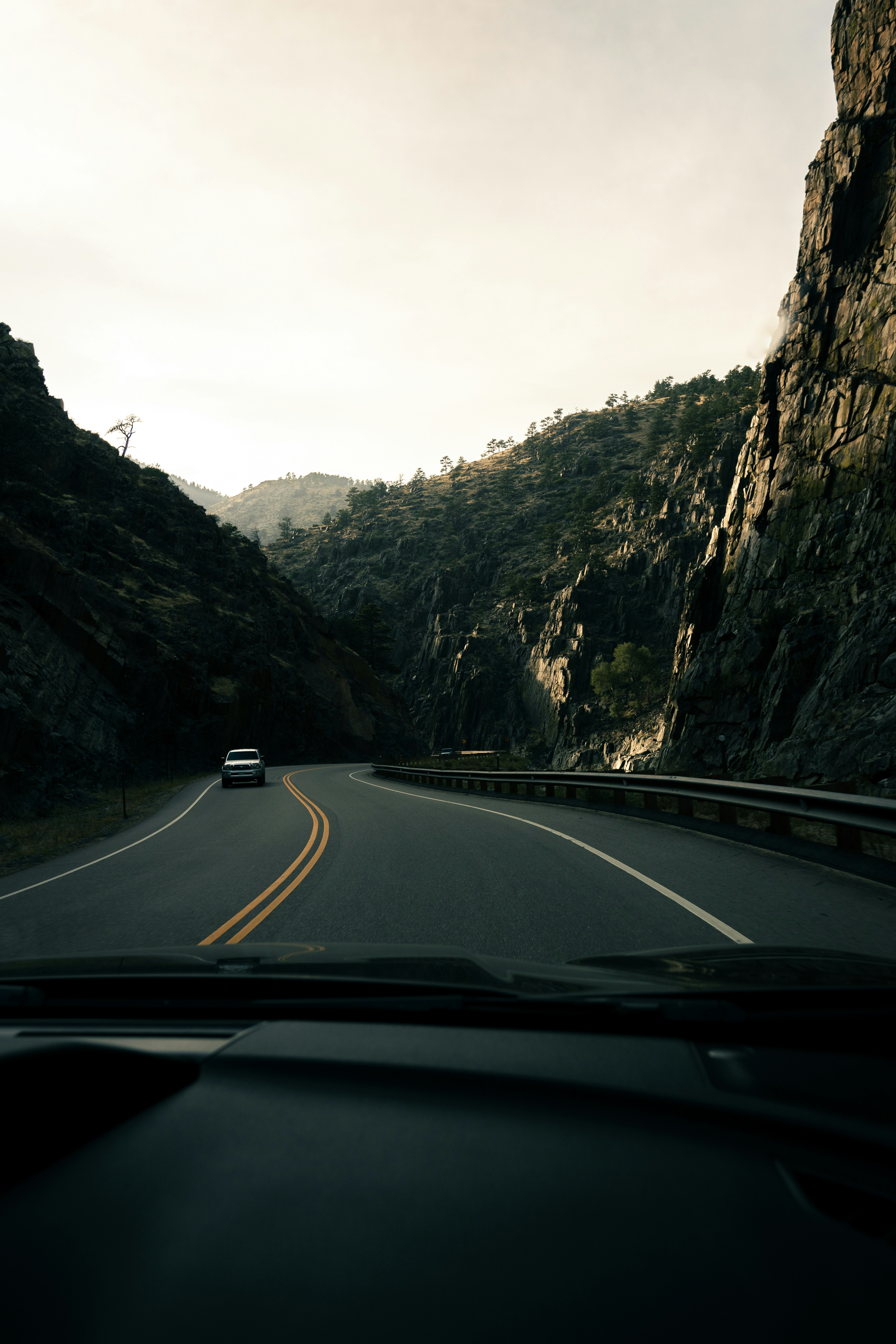 Curved road lined by steep rocky cliffs and lush greenery, capturing the essence of a scenic drive.