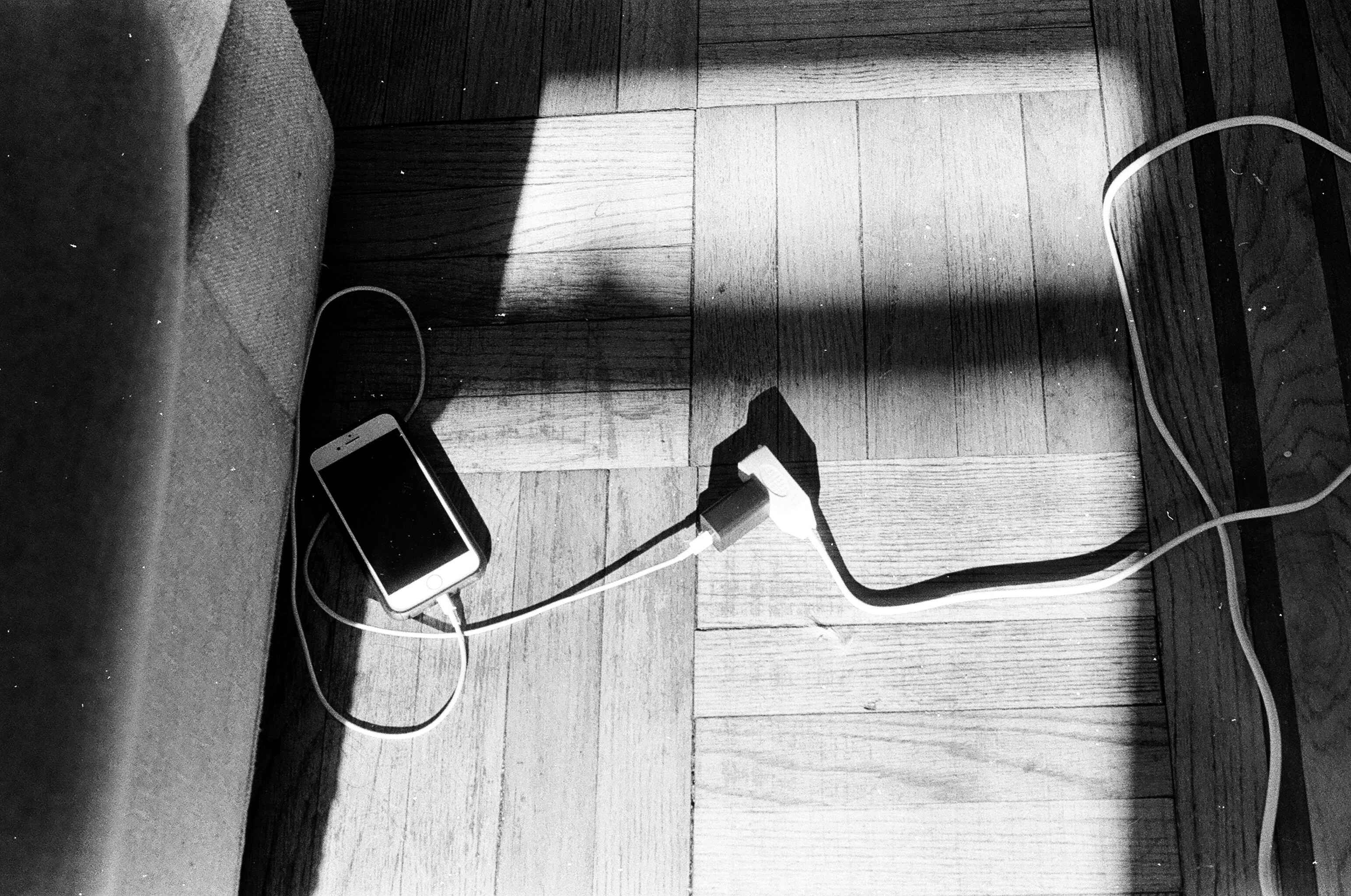 A black and white photo of a cell phone plugged into a charger photo ...