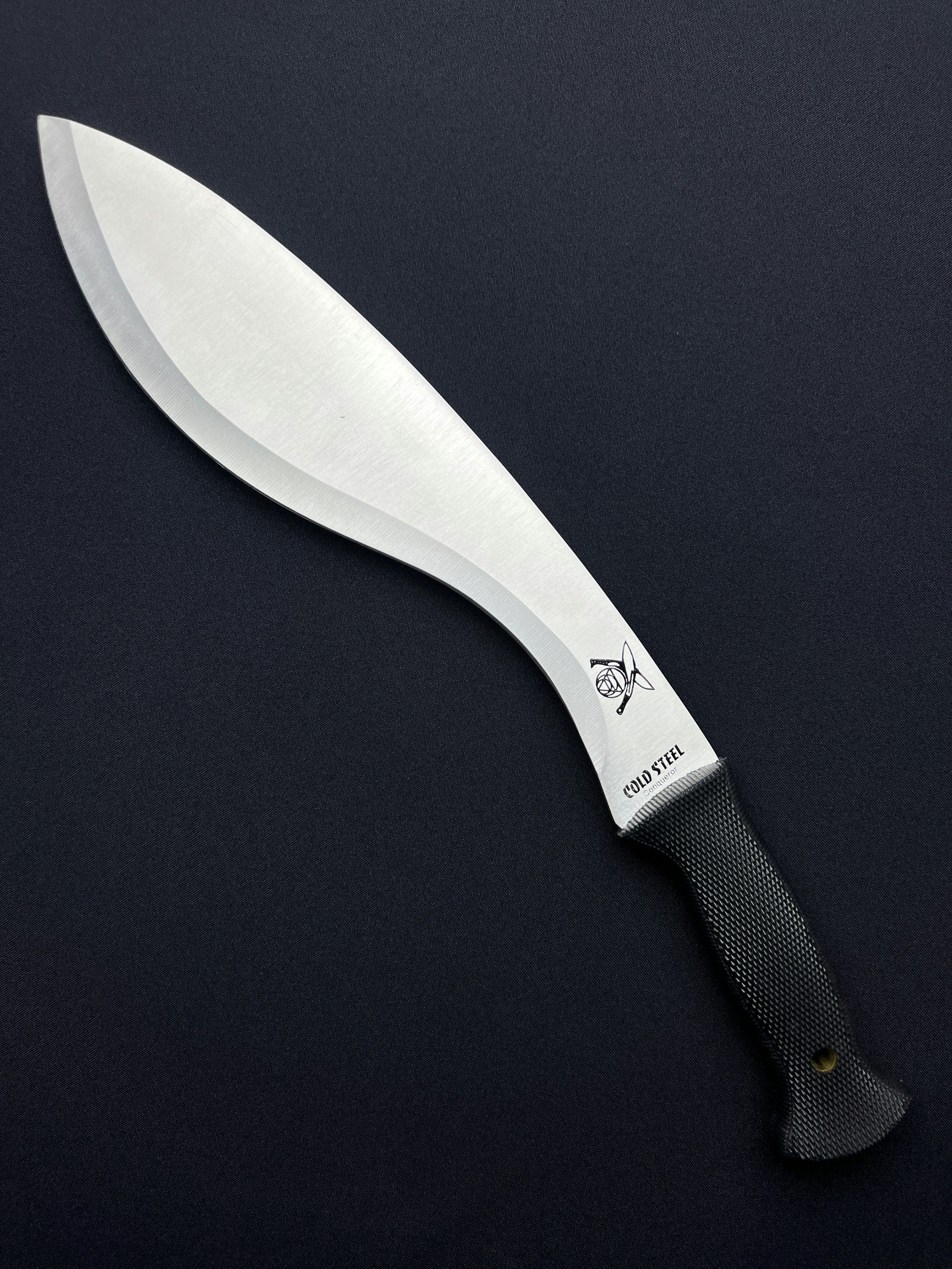 A meticulously crafted curved knife displayed against a dark backdrop, highlighting its sharp edge and textured handle.