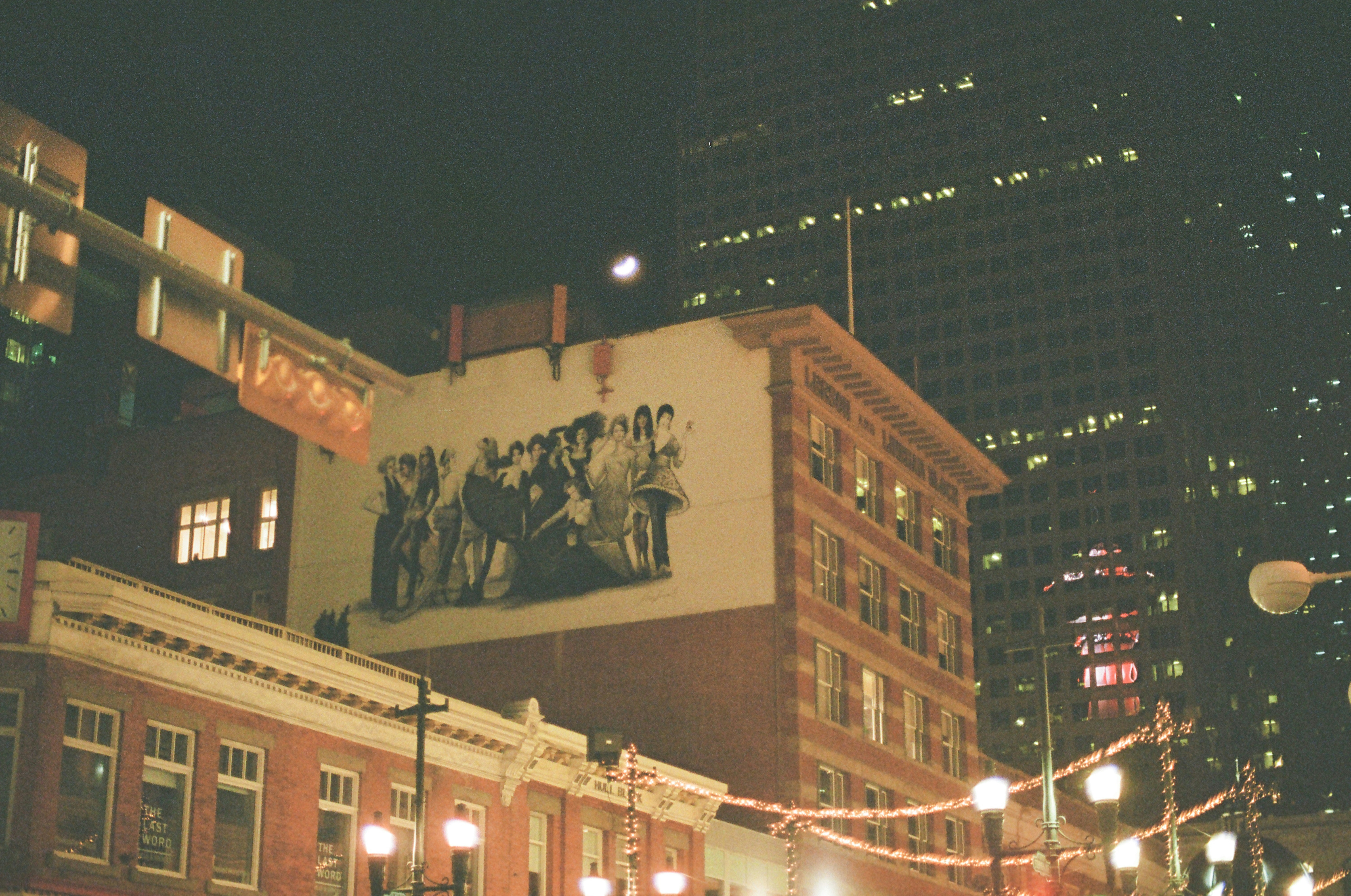 a city street at night with a large mural on the side of a building