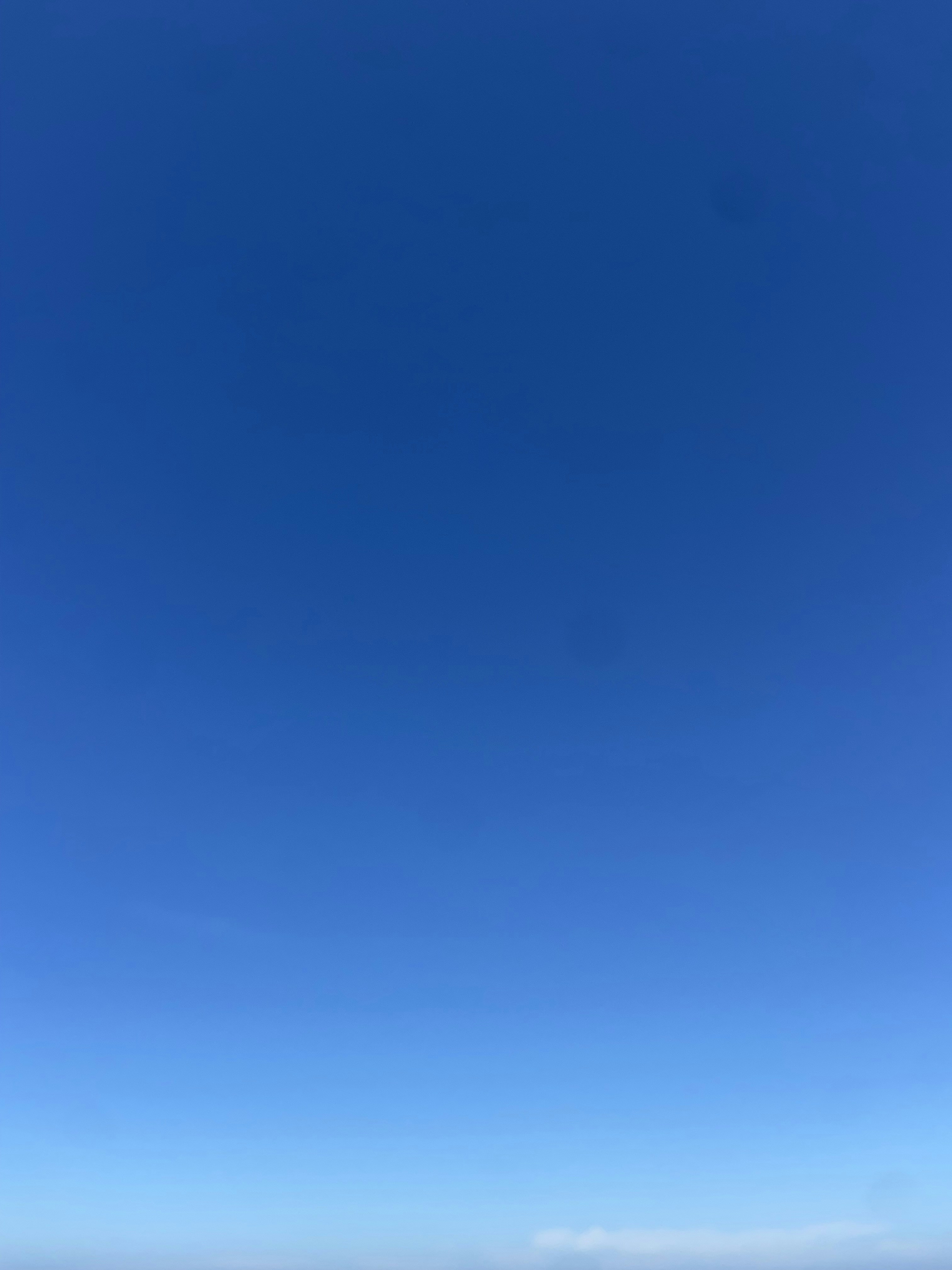 Vast expanse of clear blue sky with minimal cloud presence, creating a serene atmosphere.