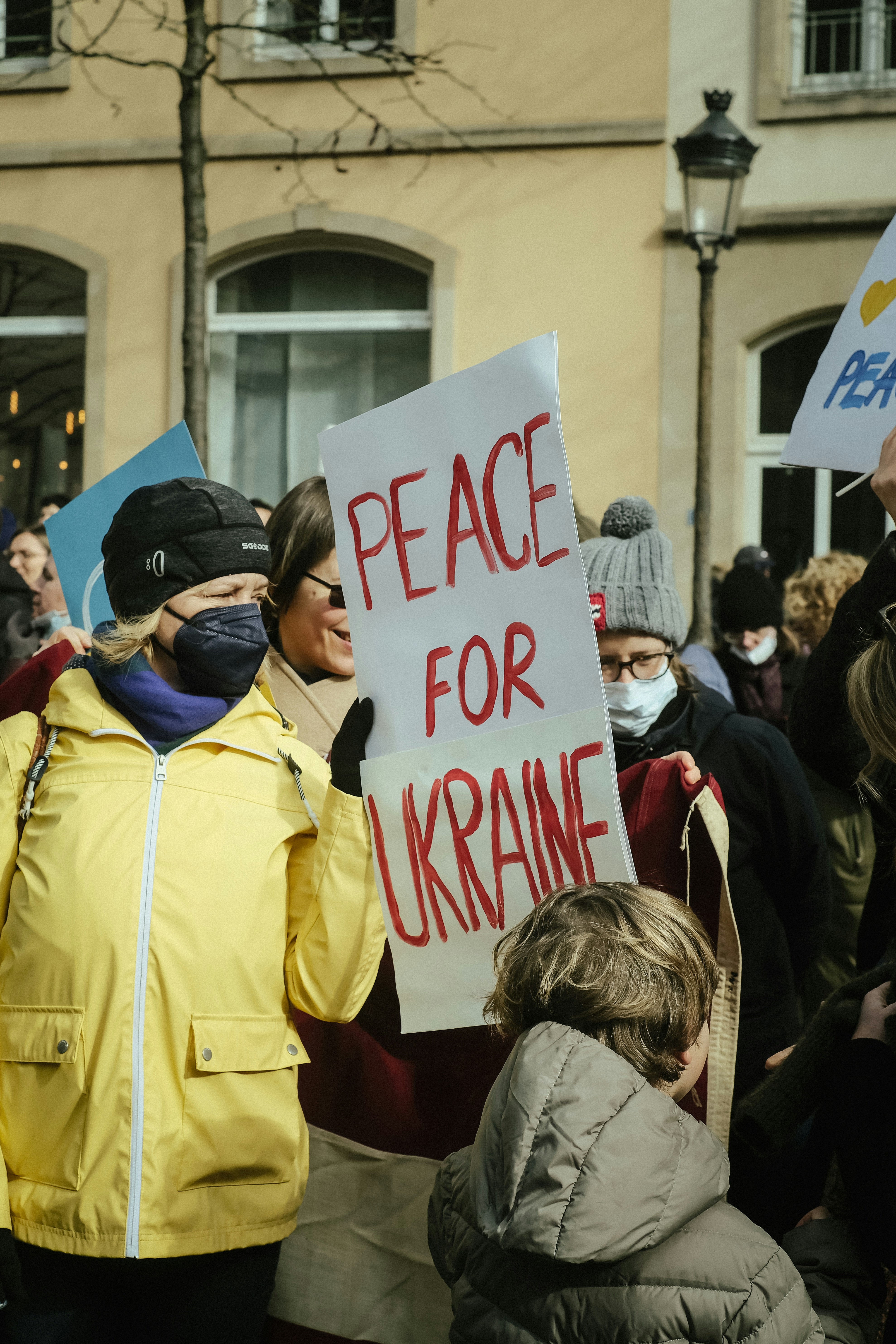 Demonstrators holding signs advocating for peace in Ukraine during a public rally.