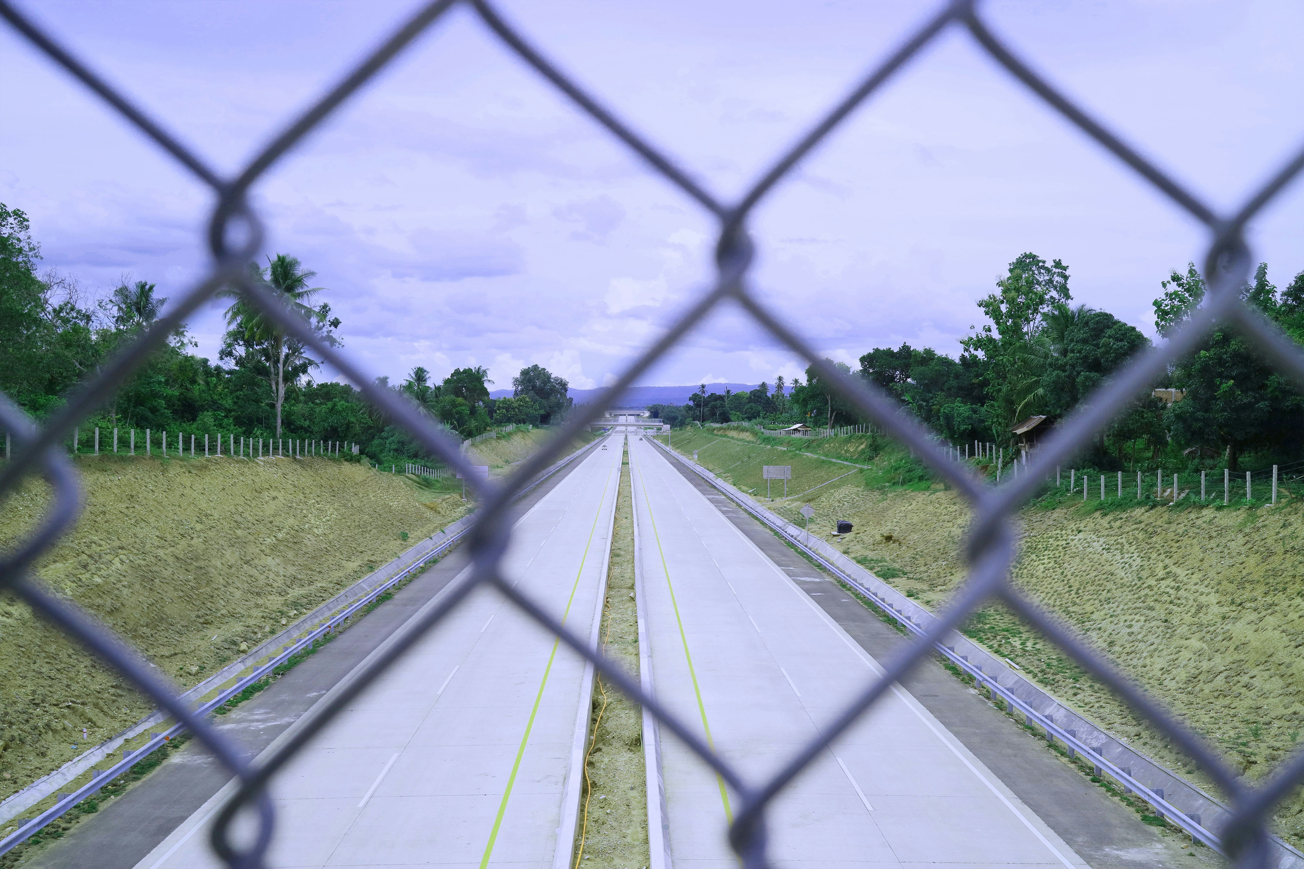 Fence-Framed Horizon: Highway Vanishing Point Beyond the Mesh