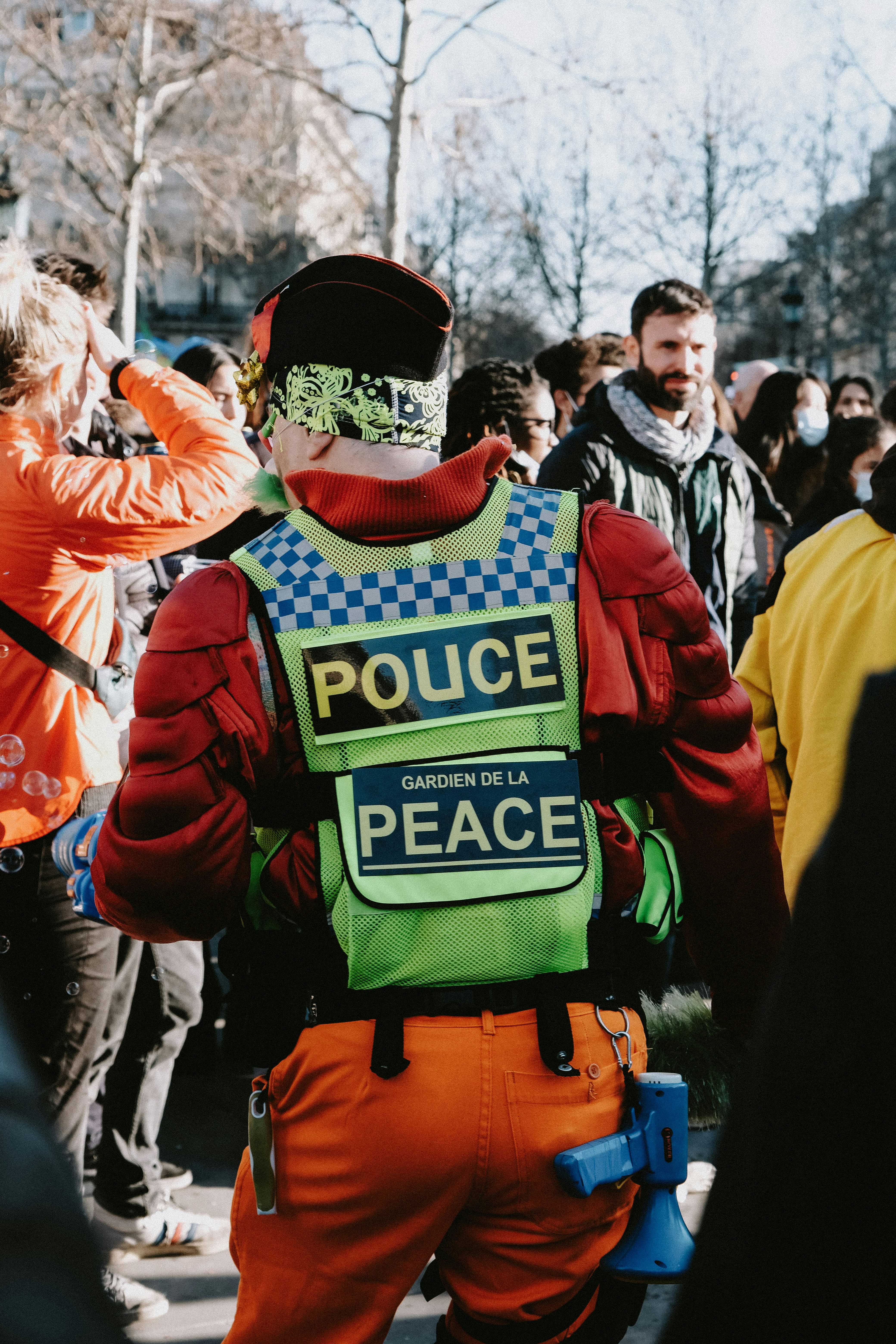 A man in a police vest standing in front of a crowd photo – Free Place ...