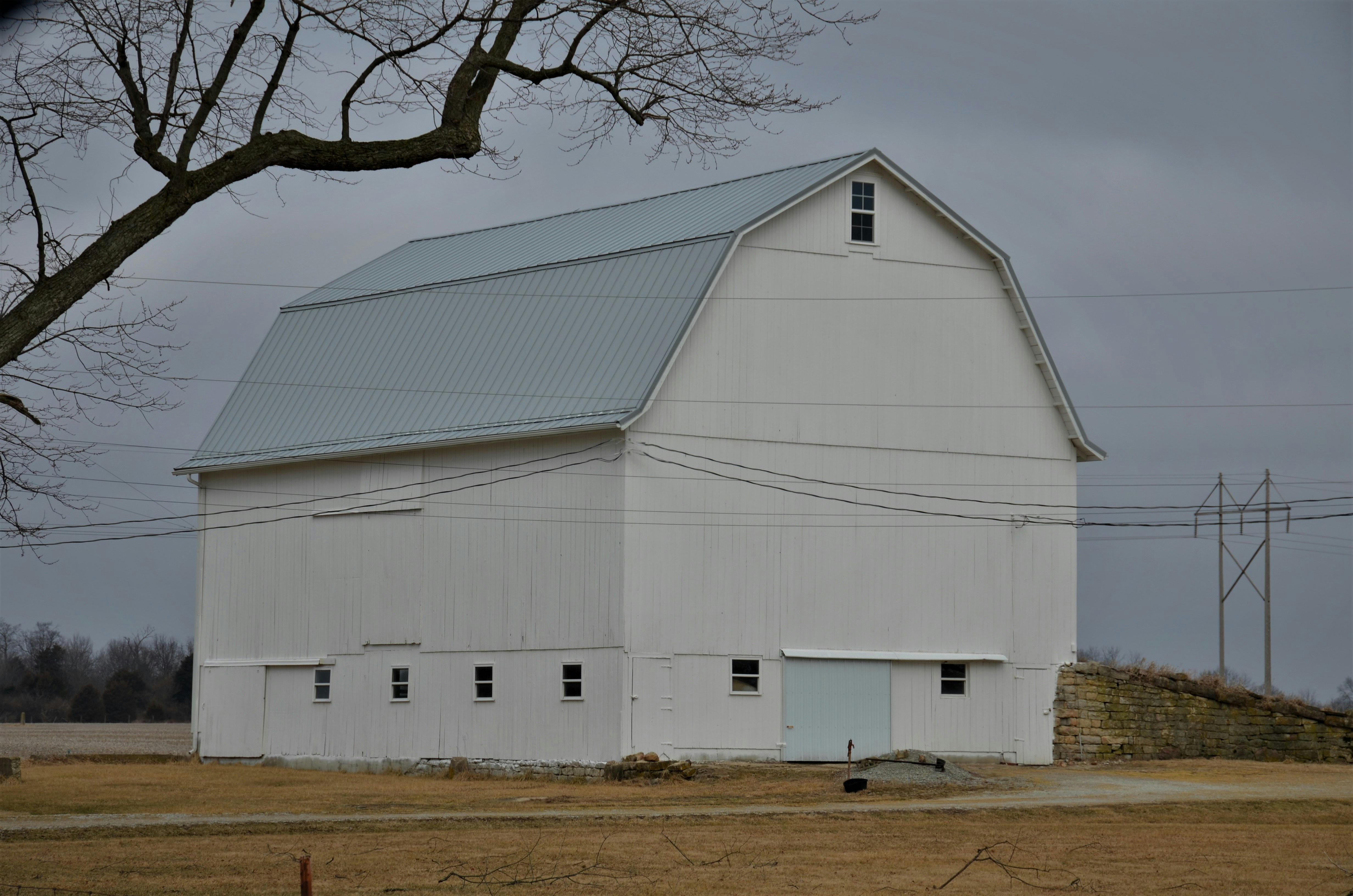 A large white barn sitting on top of a dry grass field photo – Free ...