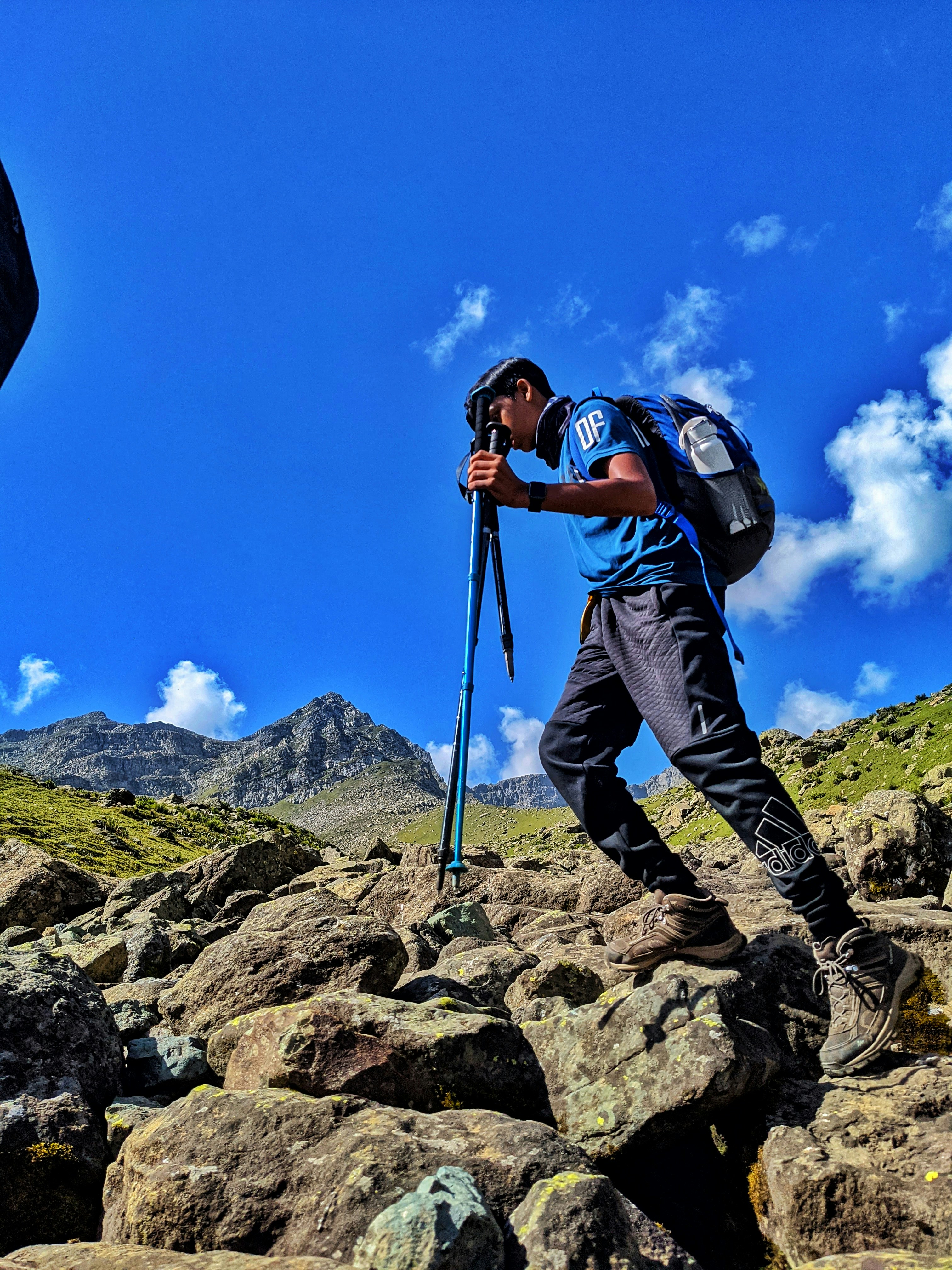 Edge of Focus: A photographer steadies a tripod on rugged scree under a cobalt alpine sky