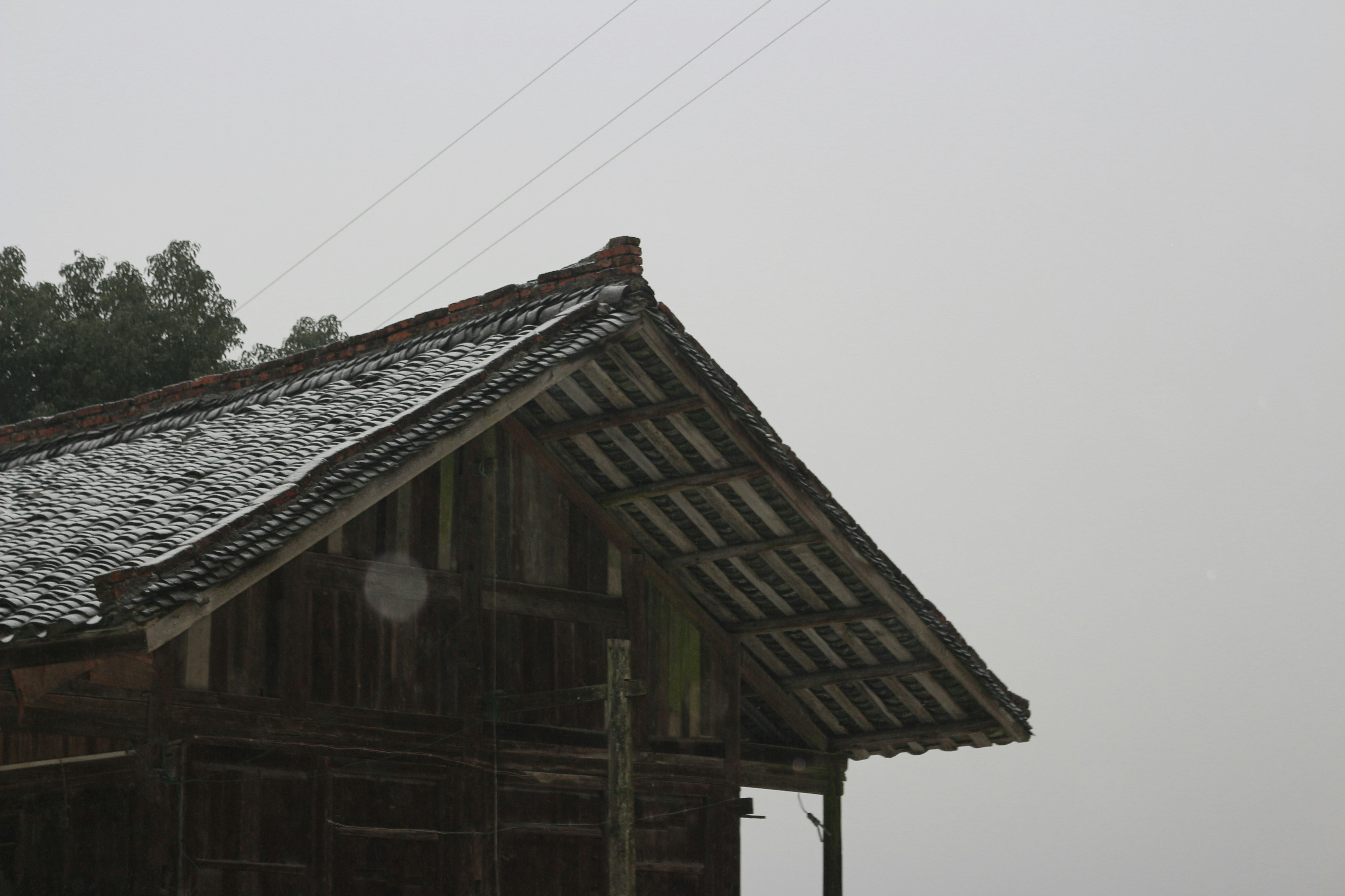 Snow-Kissed Ridge: Weathered Timber House Under a Quiet Gray Sky