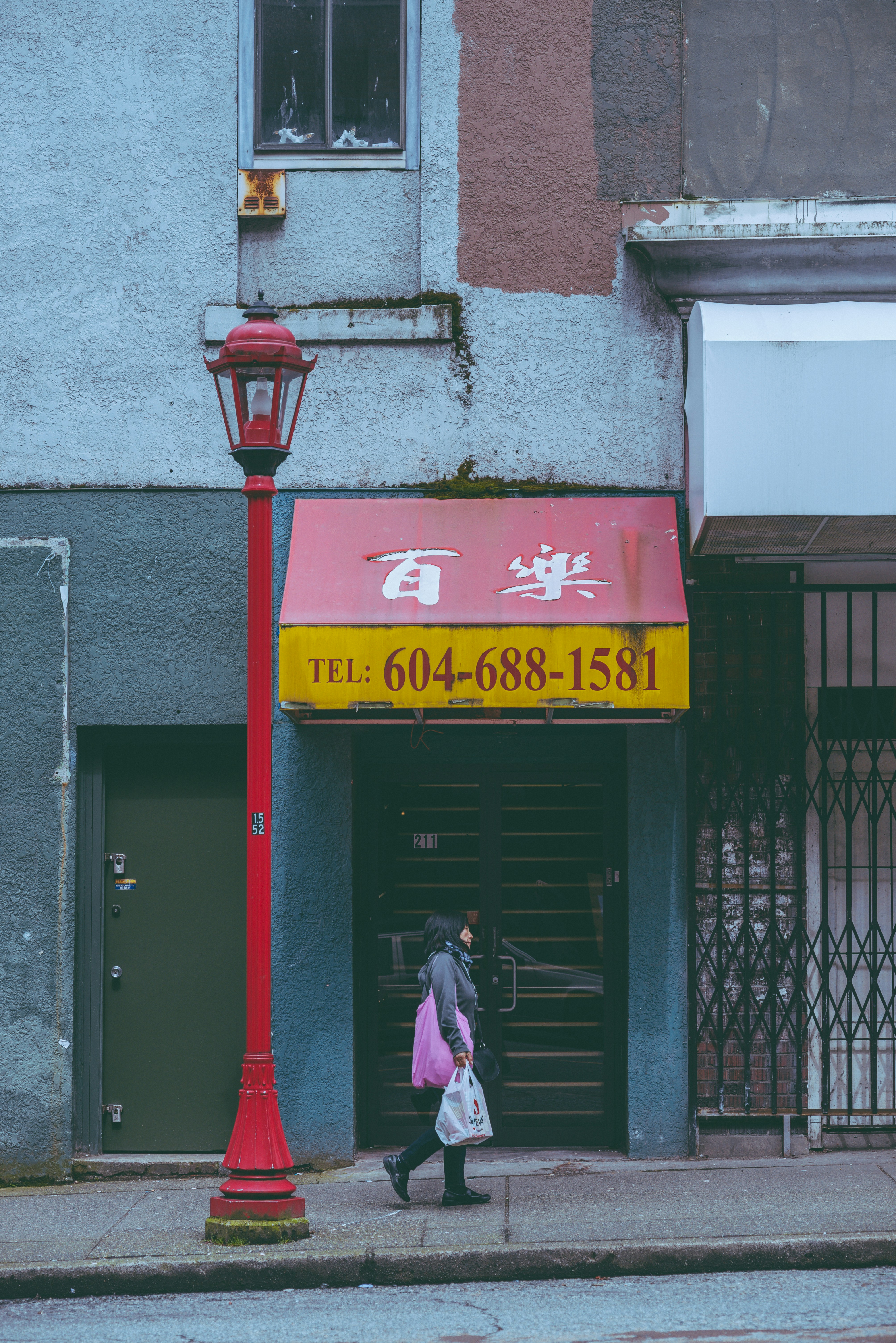 A woman walking down a street past a tall red lamp post photo – Free ...