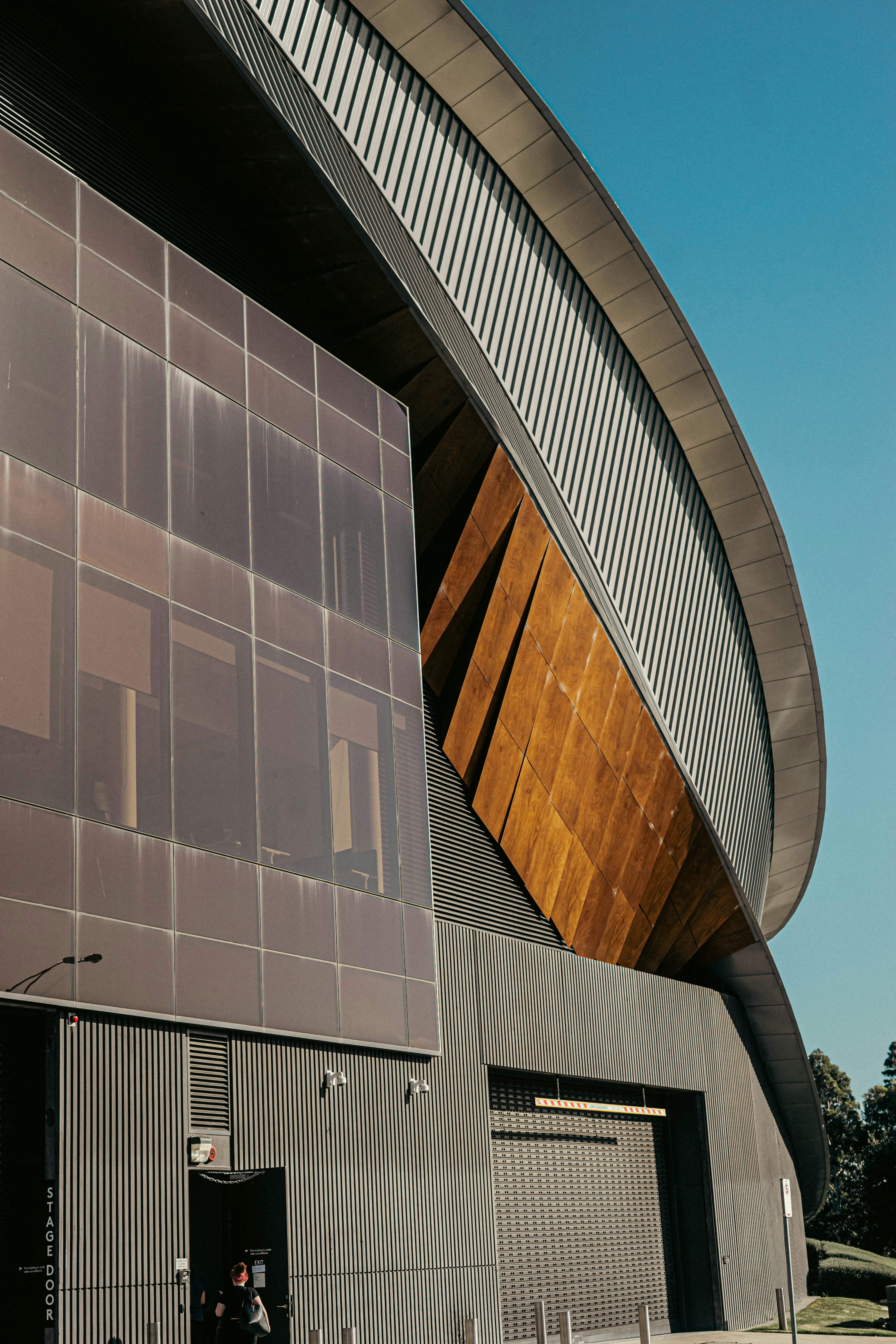 Modern architectural facade featuring a sleek, curved design with contrasting materials and textures. The interplay of glass and metal creates a striking visual effect.