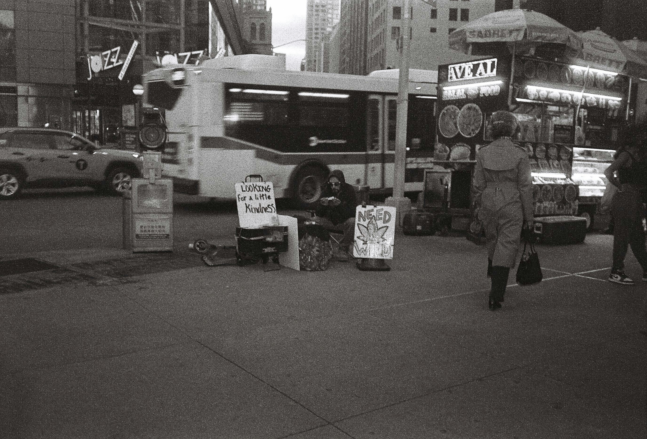 Centre Stage on a Greyscale Avenue: Bus, Signs, and Pedestrians