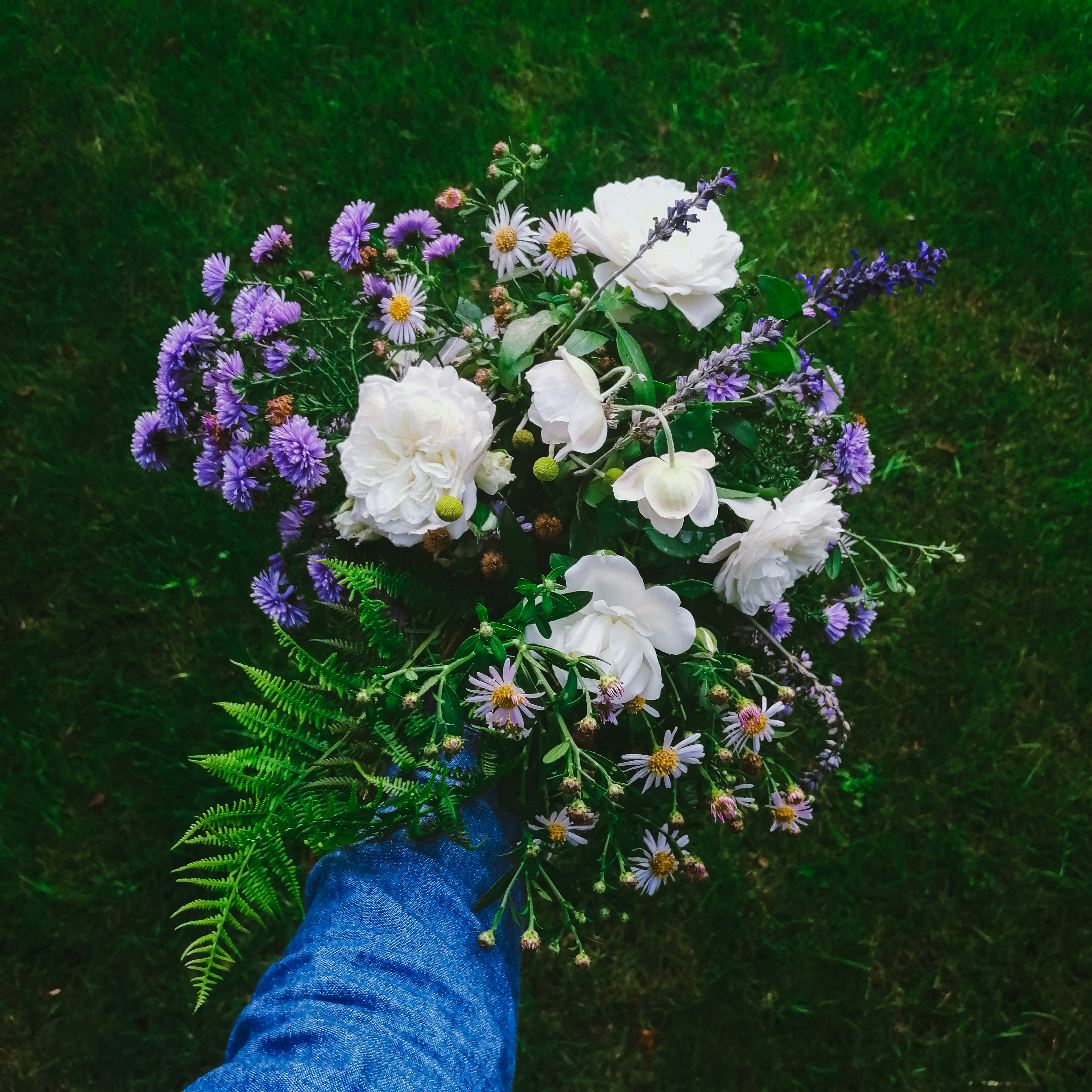 Meadow Bouquet: White Roses and Purple Sprigs Held Aloft