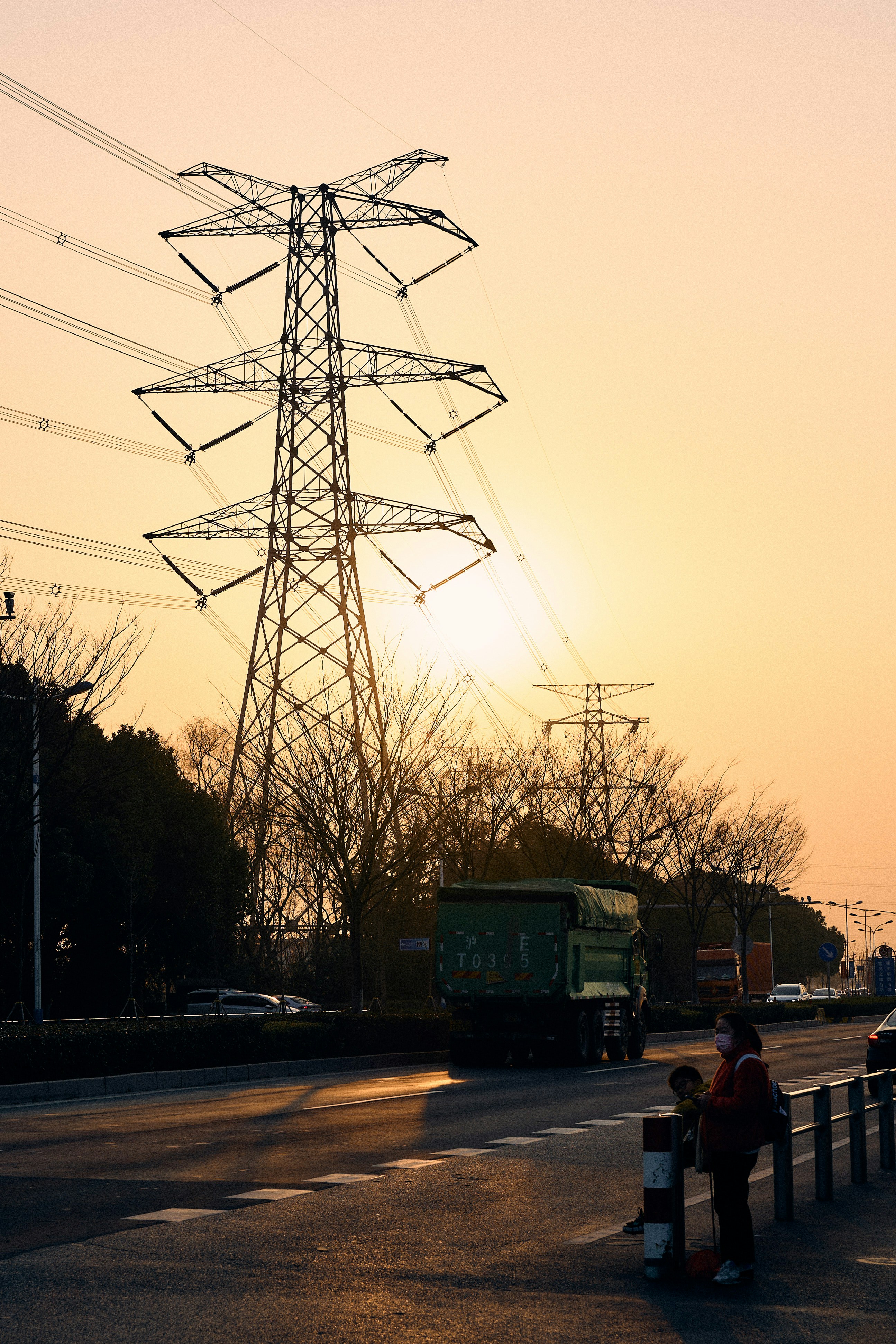 Sunset Overhead: Power Lines Rise as Cars Glide by