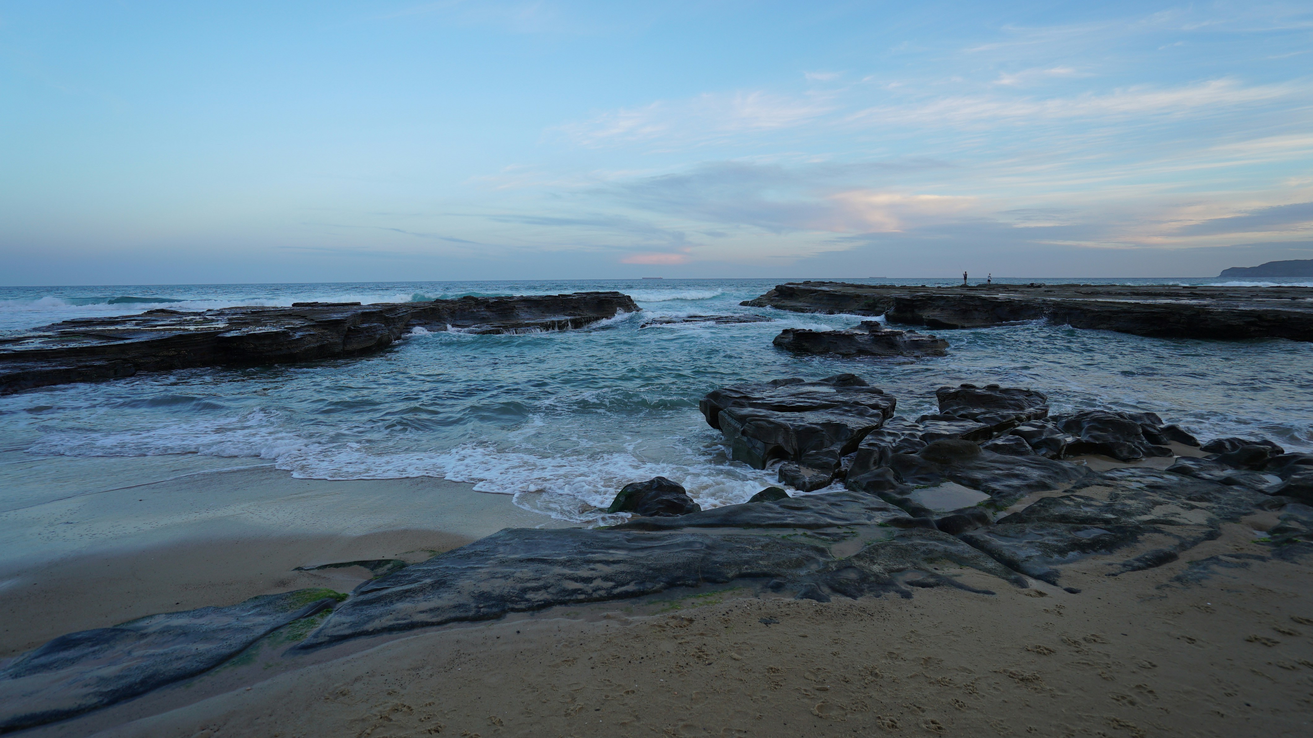 Foto zum Thema Ein felsiger Strand mit Wellen, die ins und aus dem ...