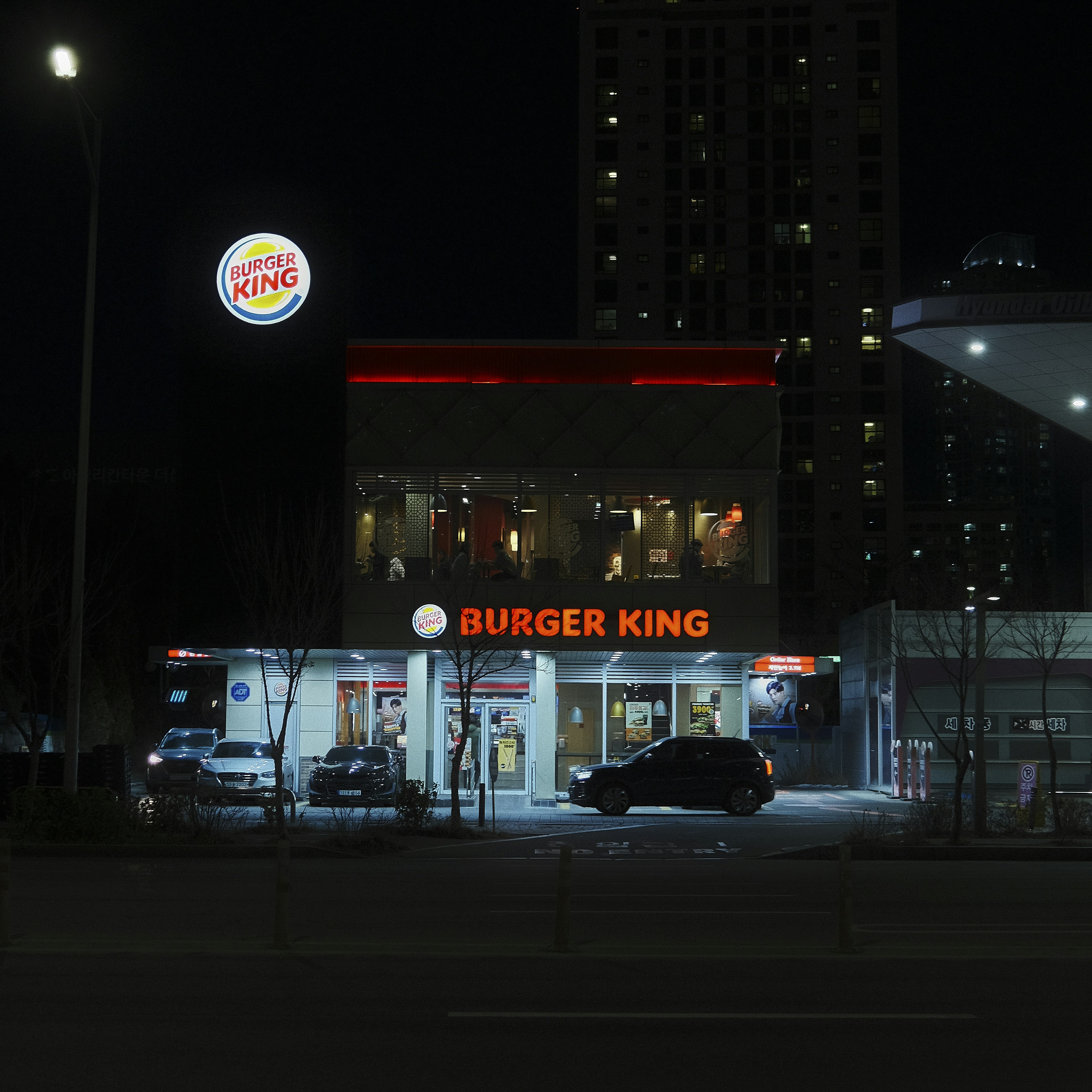 Illuminated Burger King restaurant at night, showcasing vibrant signage and a bustling atmosphere in an urban setting.
