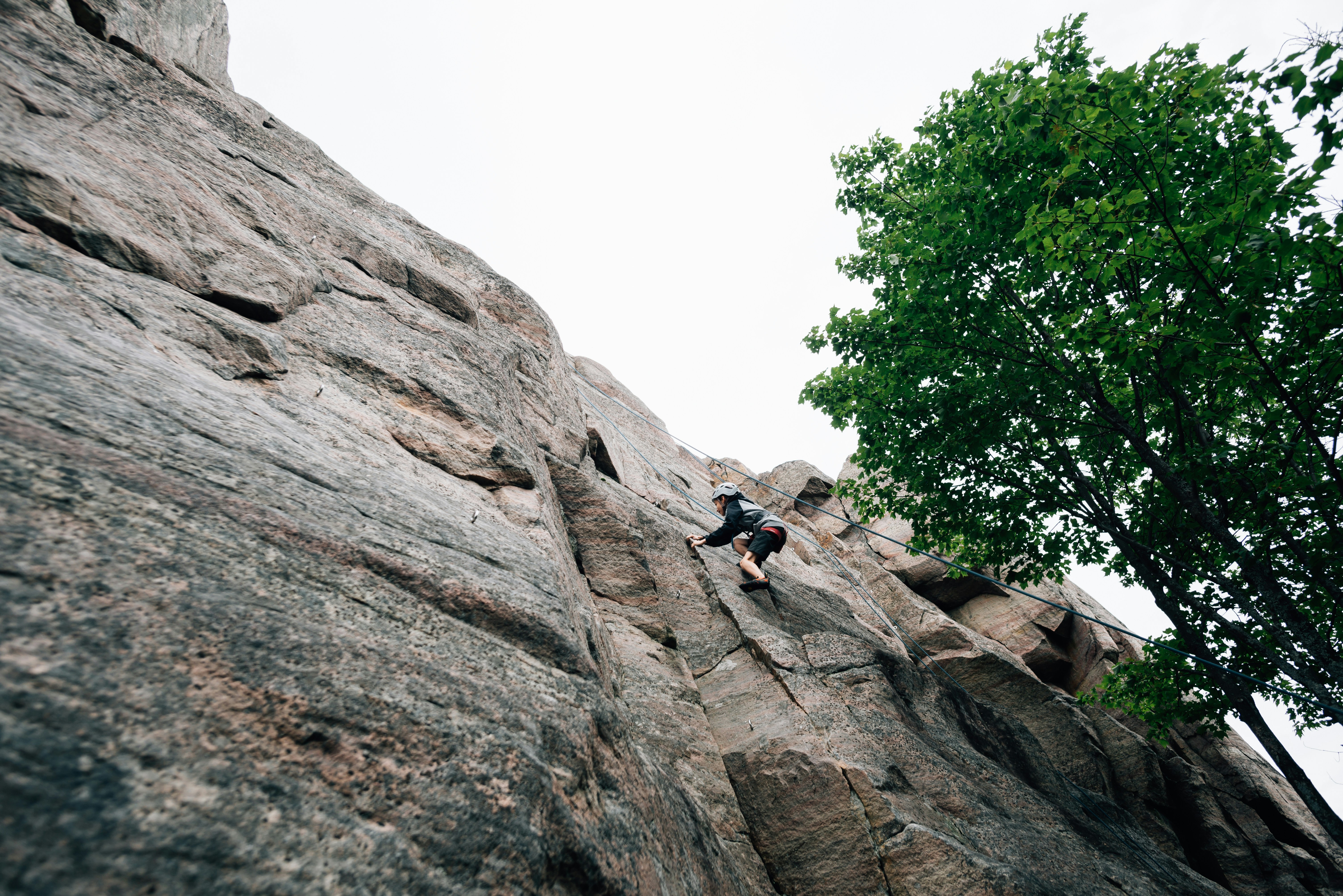 A man climbing up the side of a large rock photo – Free Témiscamingue ...