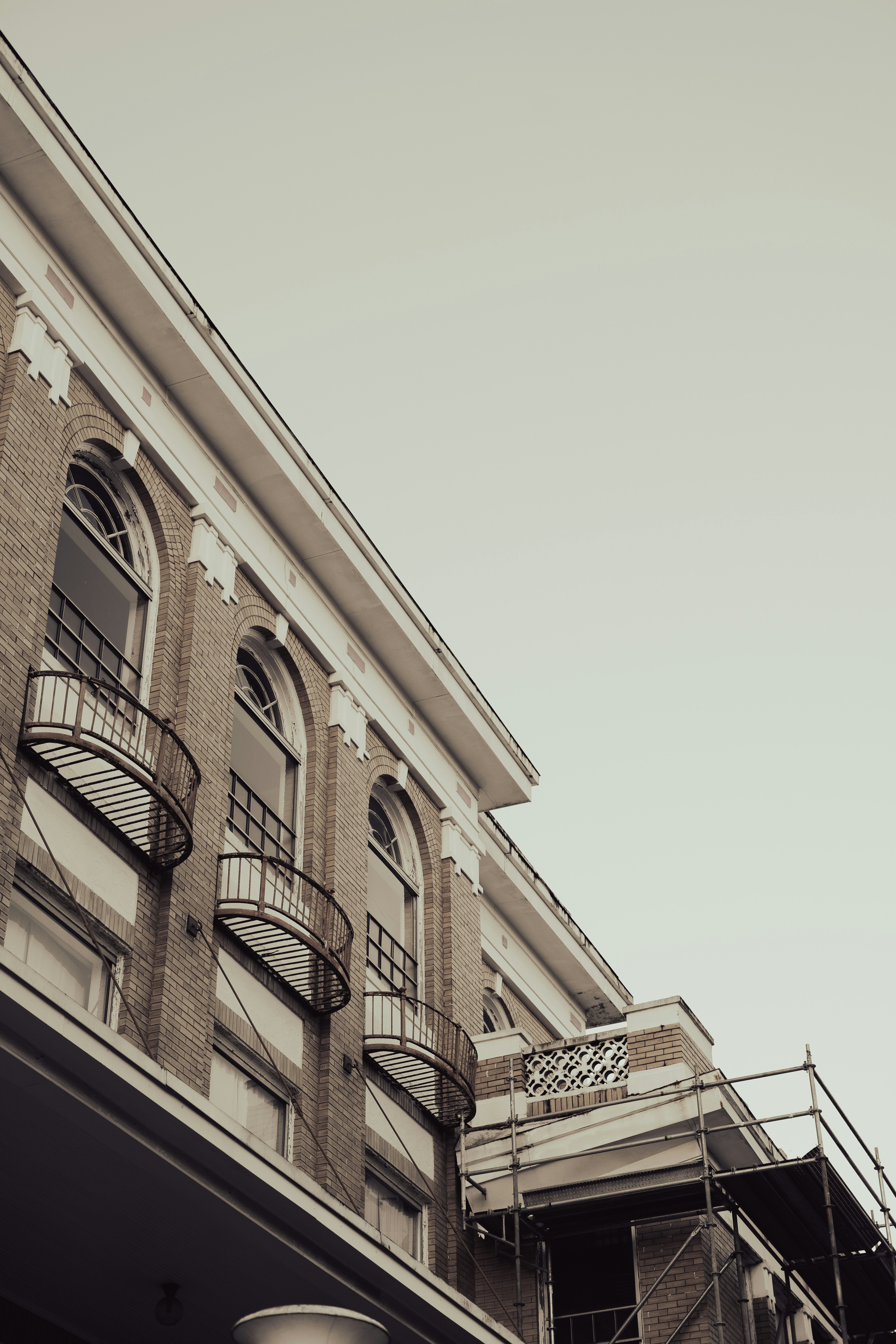 Architectural Rhythm: Brick Arches and Scaffolding Against a Pale Sky