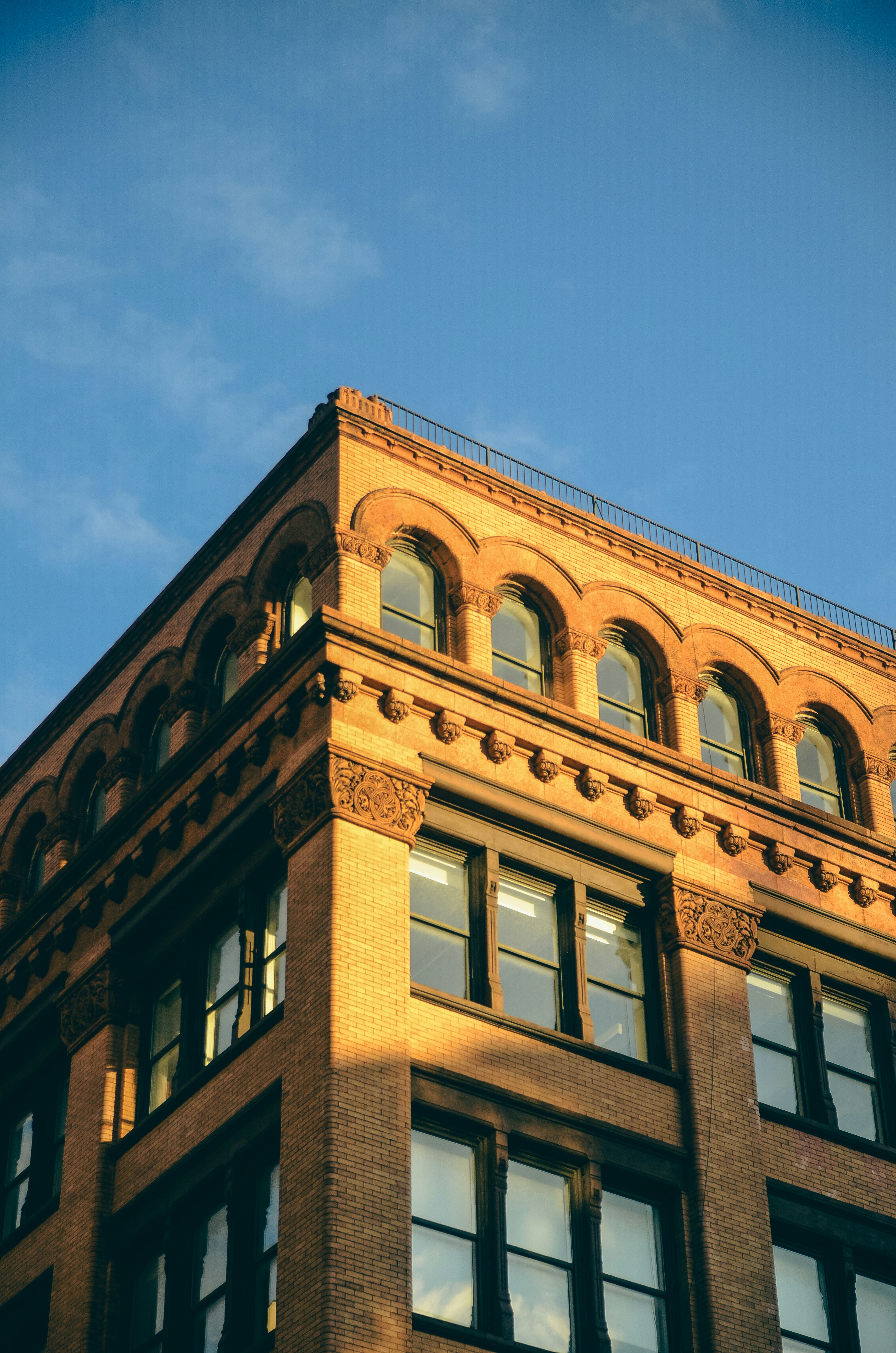 Historic brick building adorned with arched windows, illuminated by the warm glow of the setting sun.