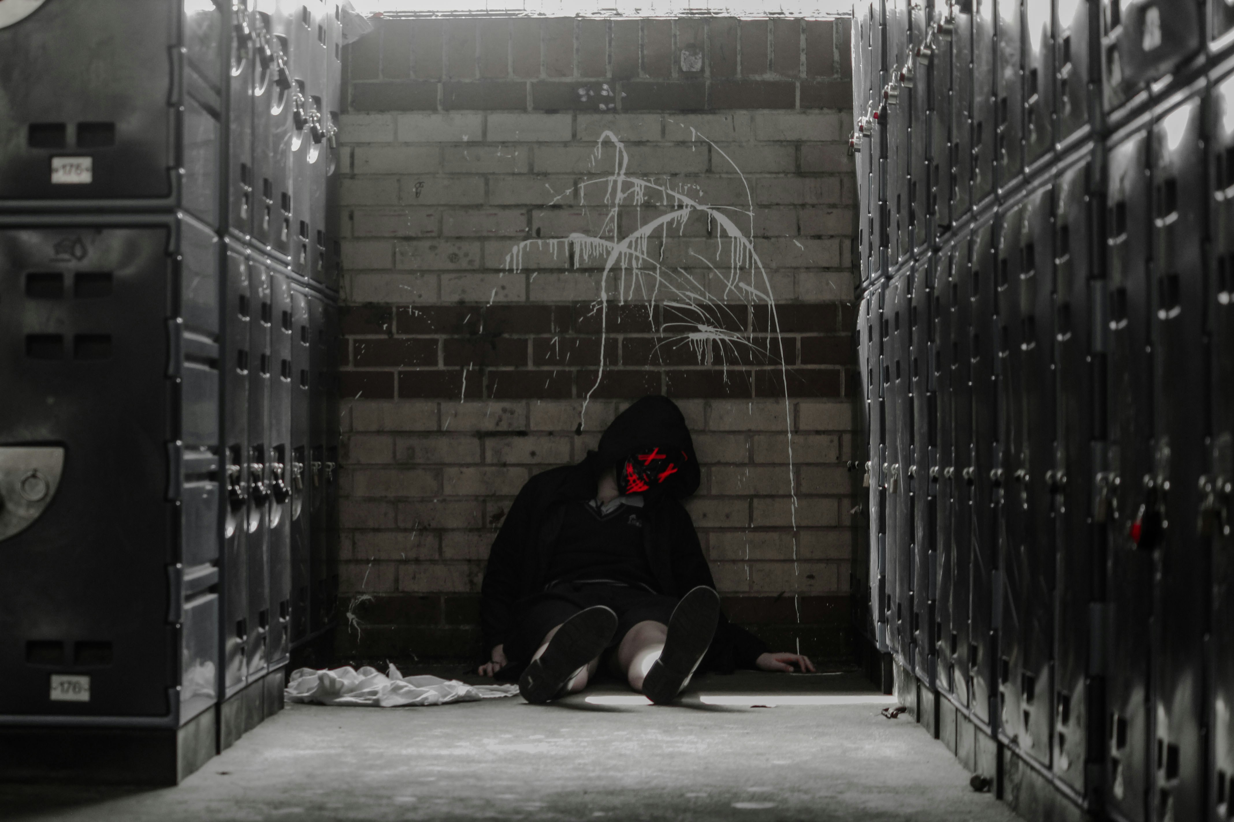 A person sitting on the ground in a room with lockers photo – Free ...