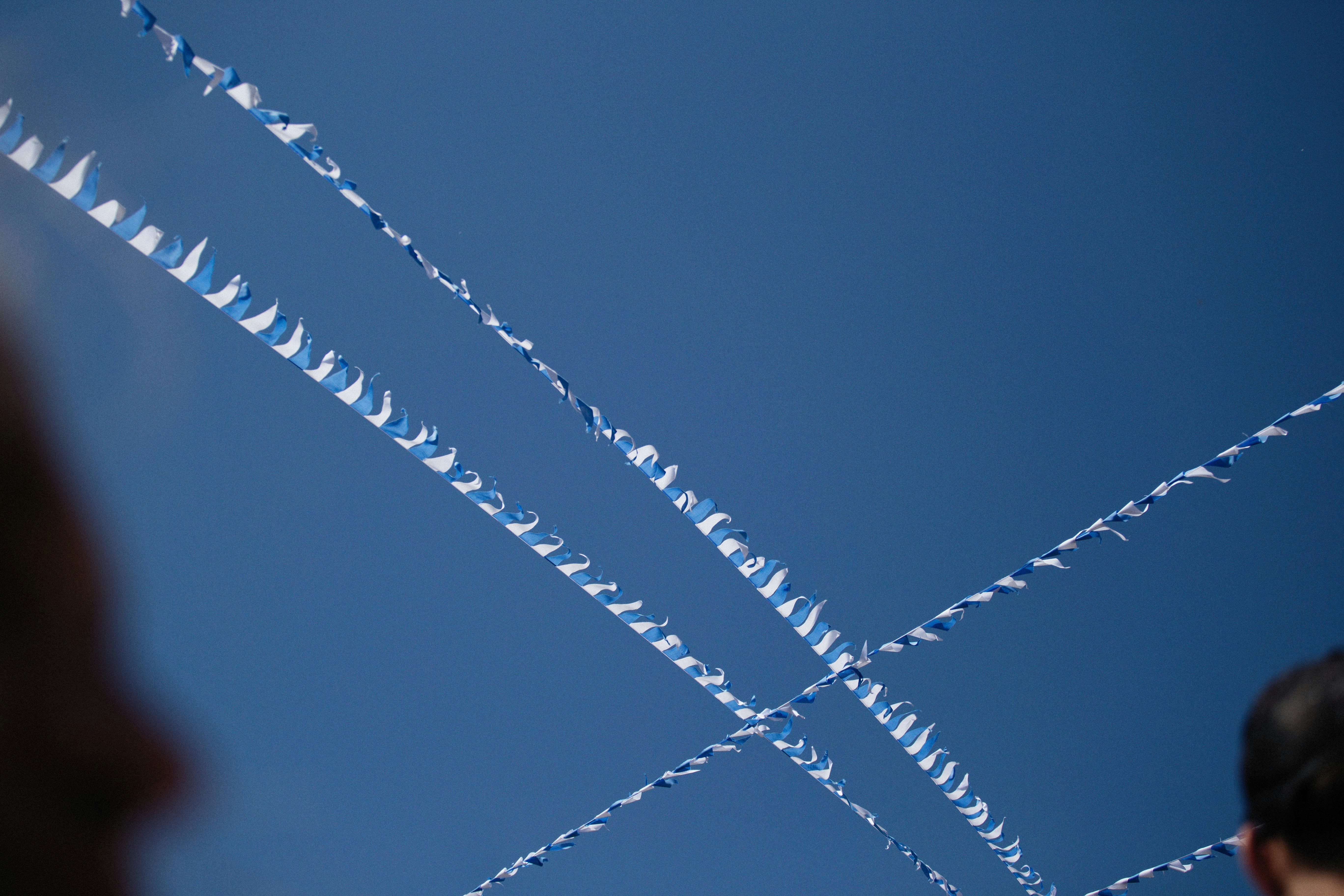 Colorful flags fluttering against a clear blue sky, creating a dynamic pattern that evokes a festive atmosphere.