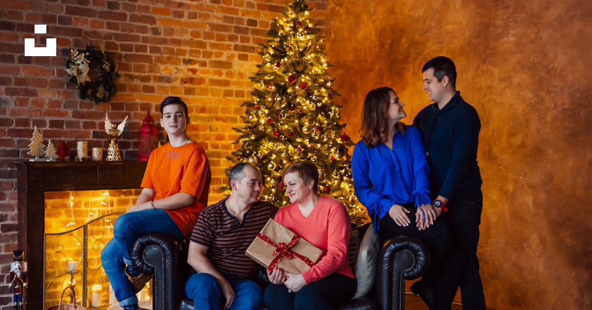 Un Groupe De Personnes Assises Sur Un Canapé Devant Un Sapin De Noël