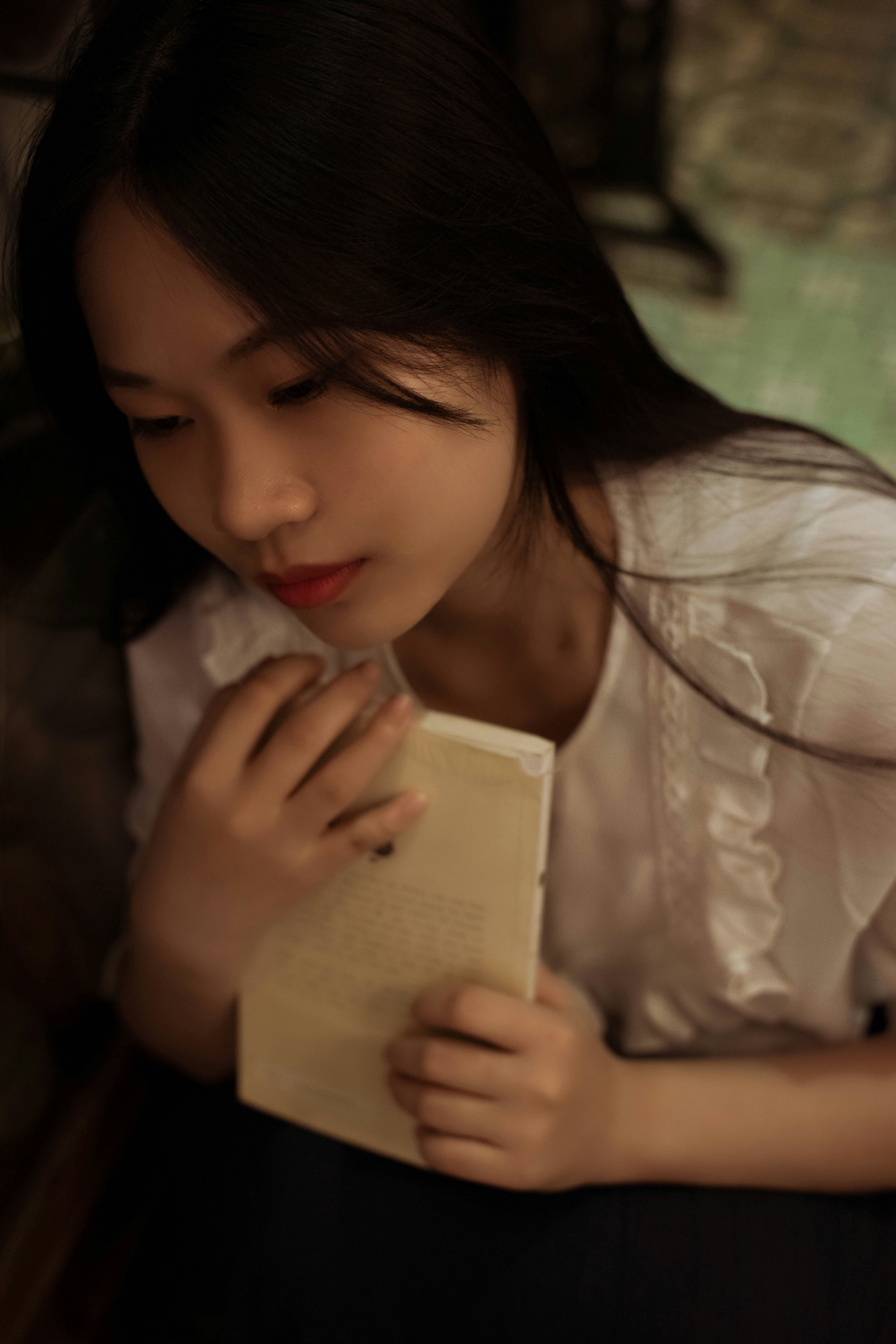 Foto Una mujer leyendo un libro mientras está sentada – Imagen Triste gratis en Unsplash