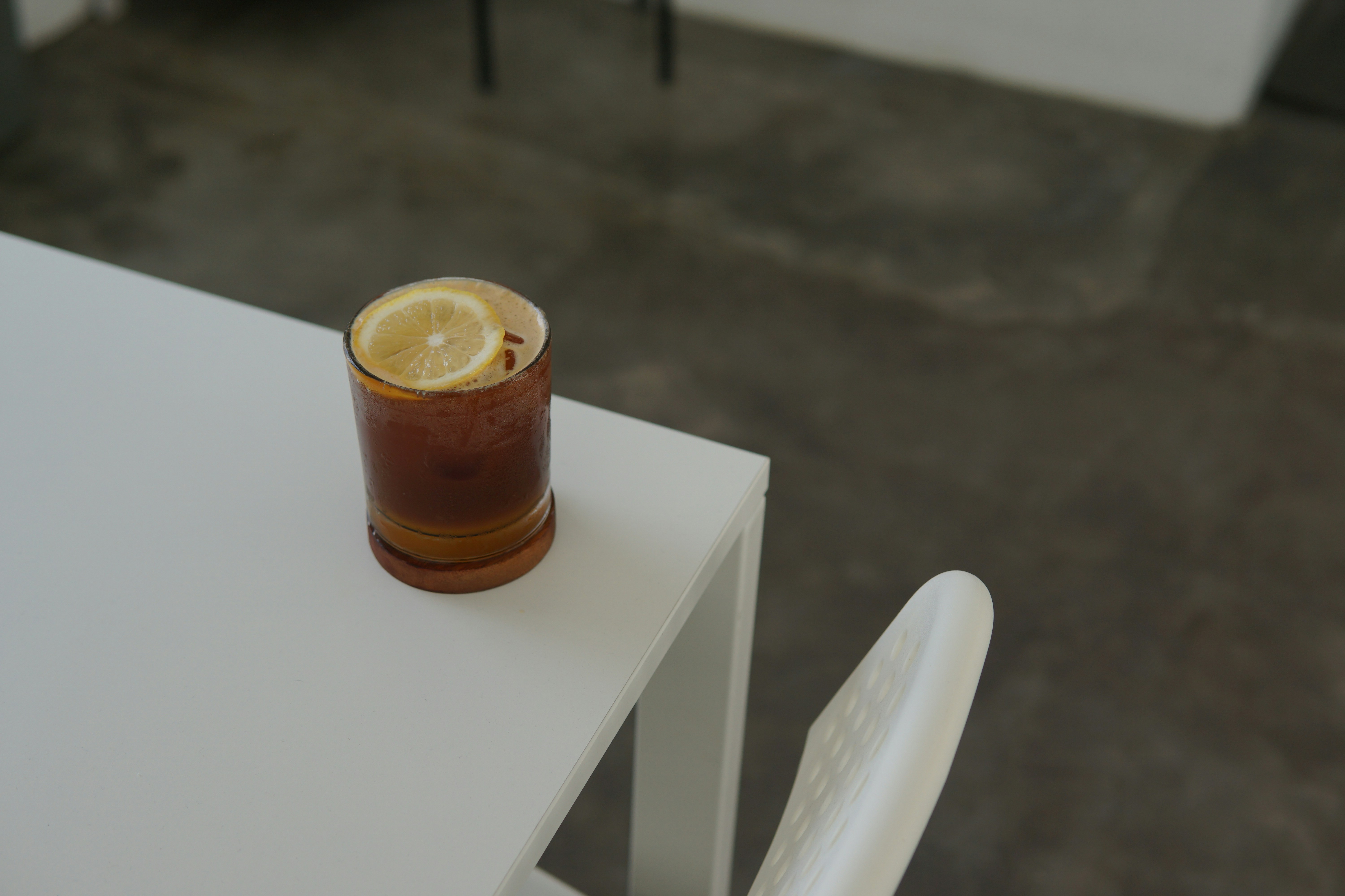 Lemon-iced tea rests on a stark white table, framed by a lone chair