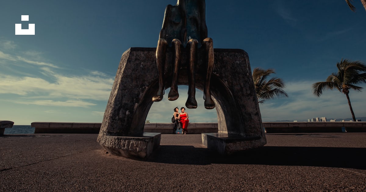 Una Pareja Parada Frente A Una Estatua De Dos Personas Foto Imagen De