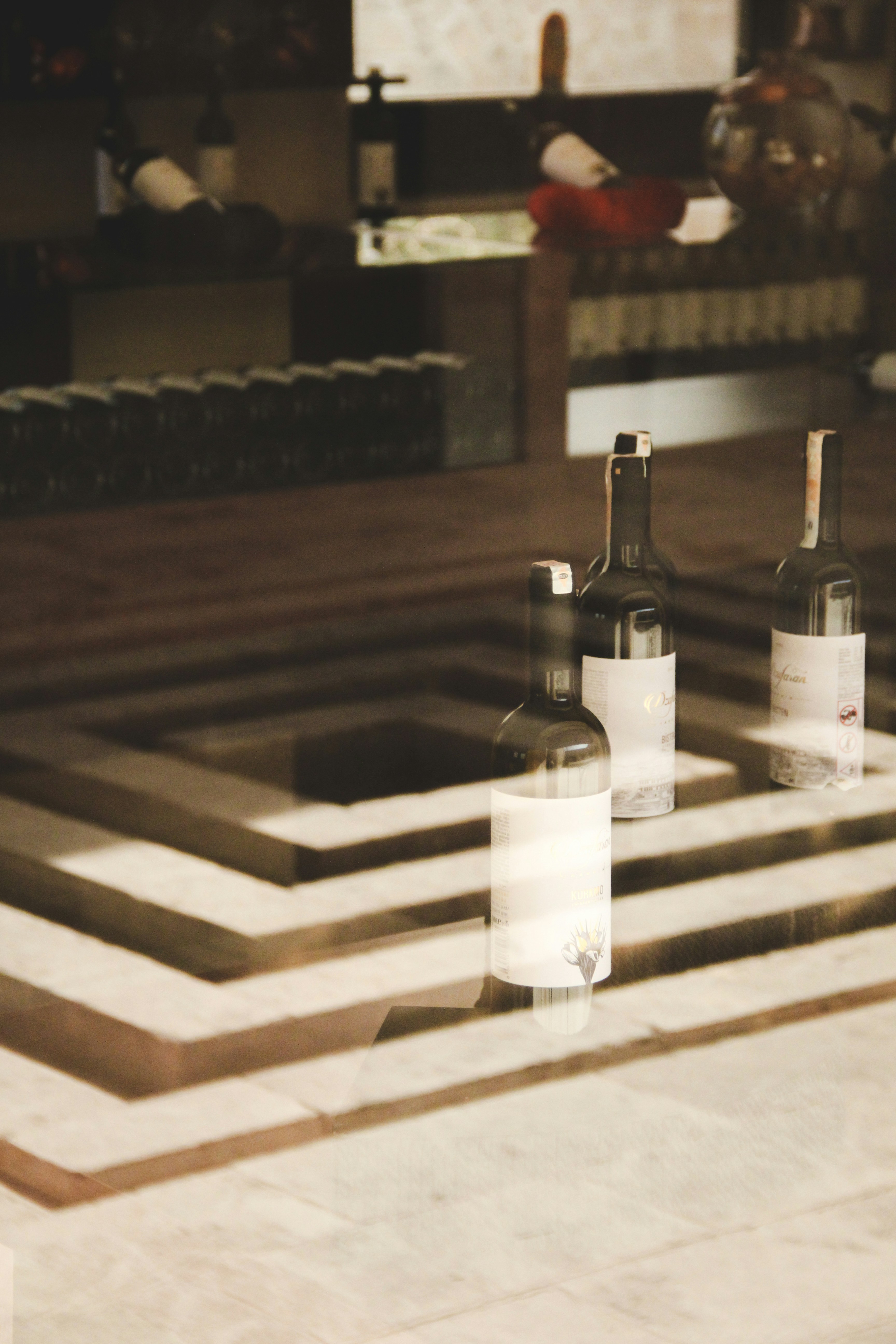 Wine Bottles in a Dimly Lit Cellar: Subtle Reflections and Steel Rims