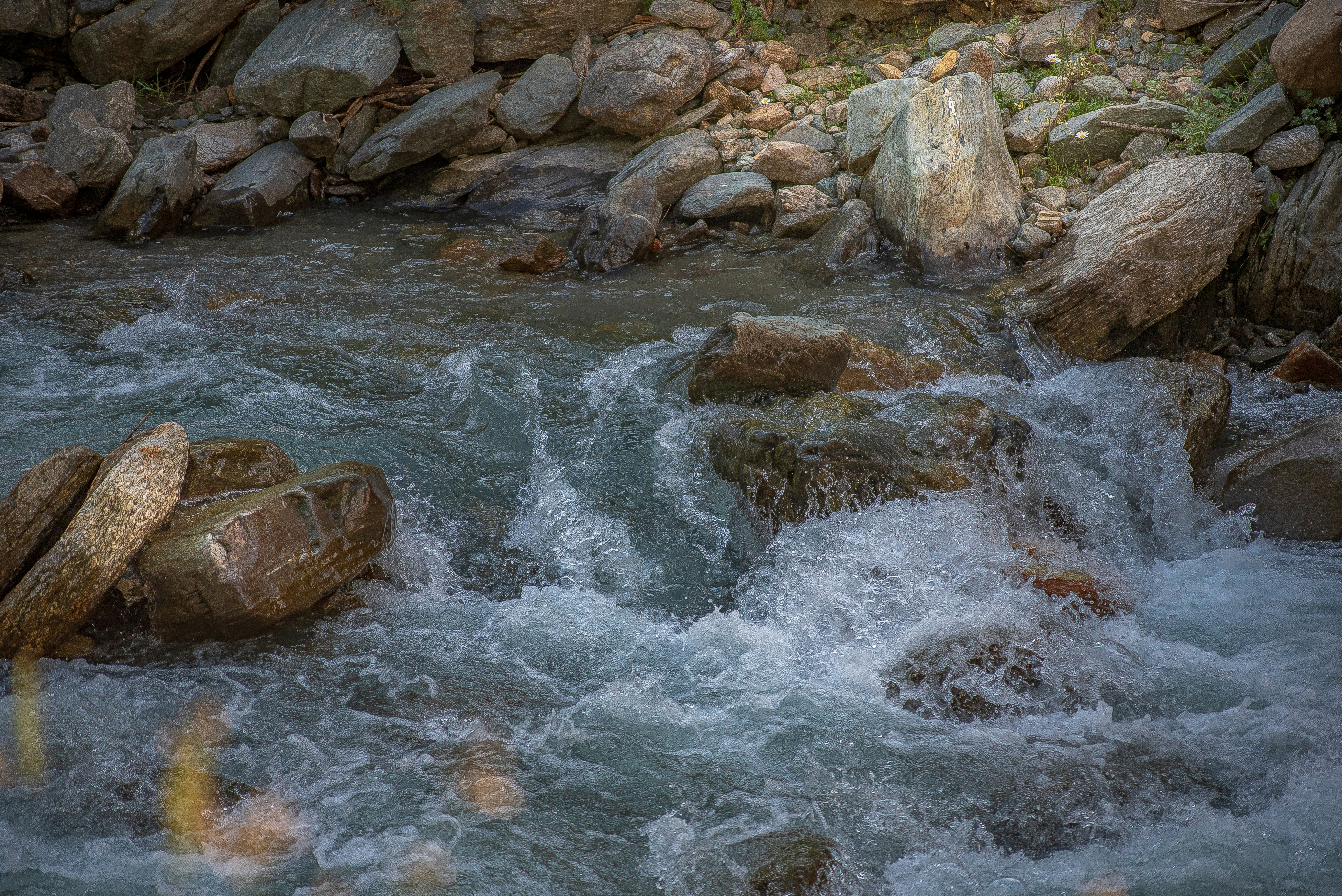A stream of water running between rocks and grass photo – Free Nature ...