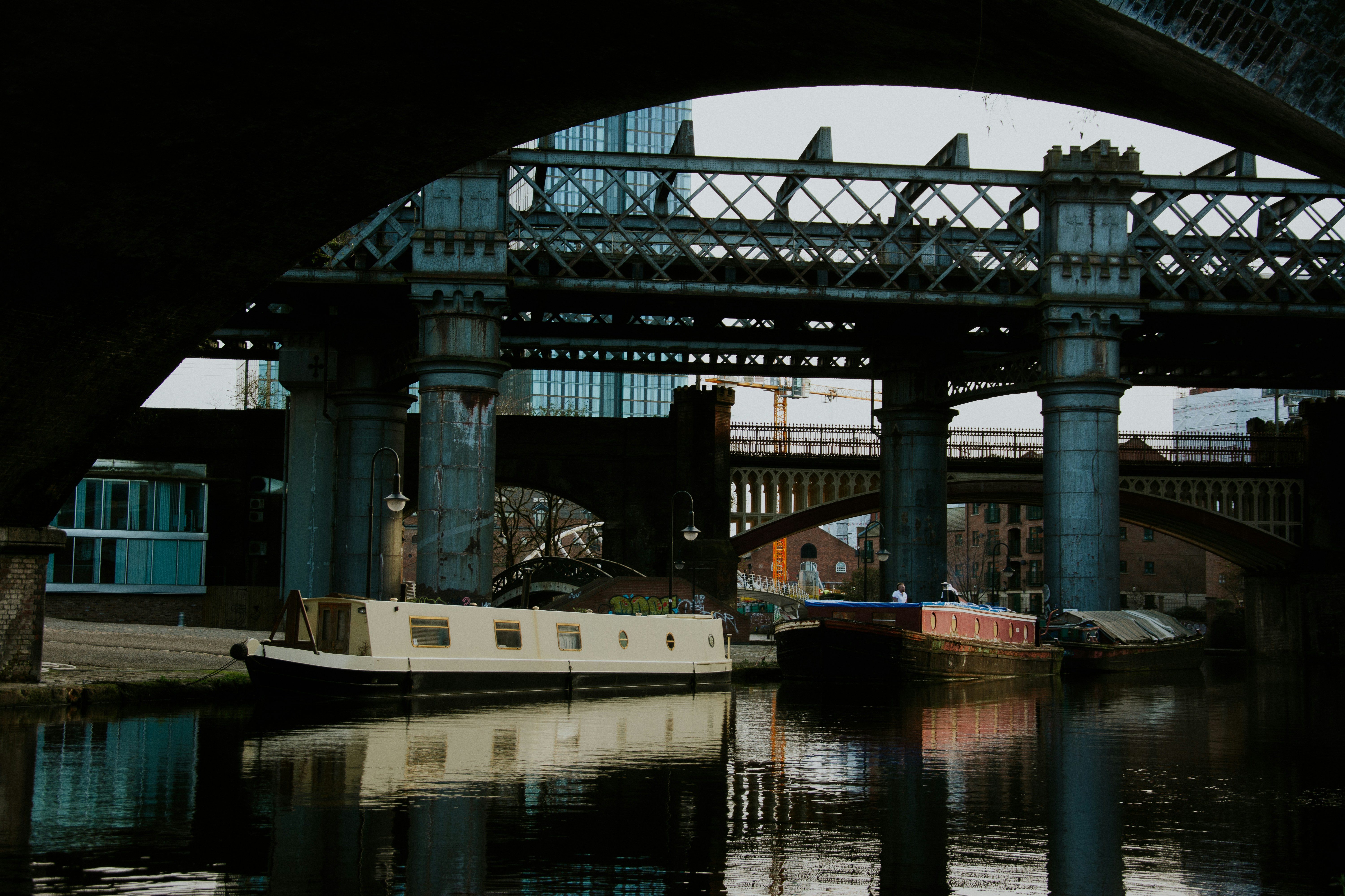 A boat floating under a bridge next to a river photo – Free Castlefield ...