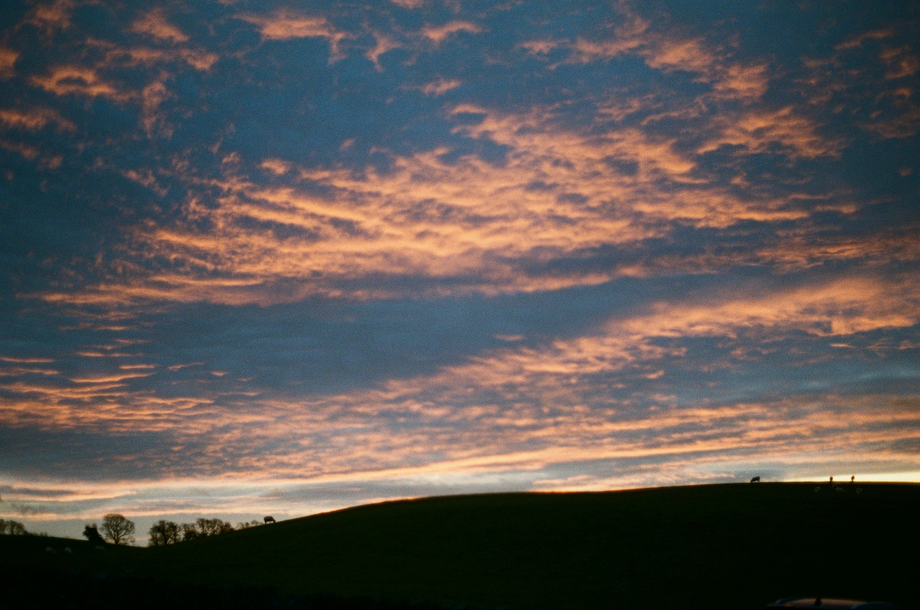 Horizon Ember: Cloud-streaked sunset over a silent ridge