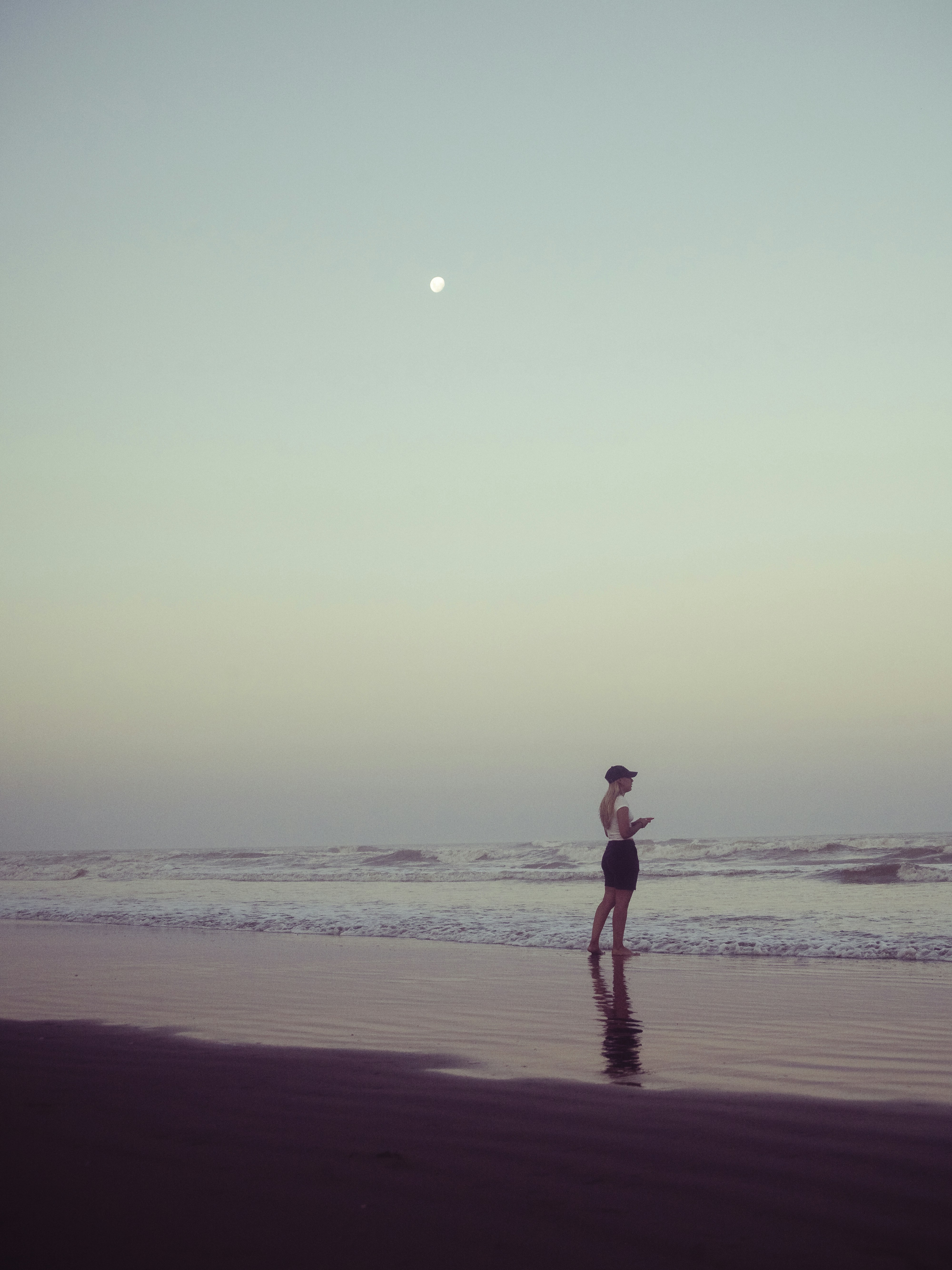 Moonlit Shoreline: A Lone Figure Anchored by Gentle Waves