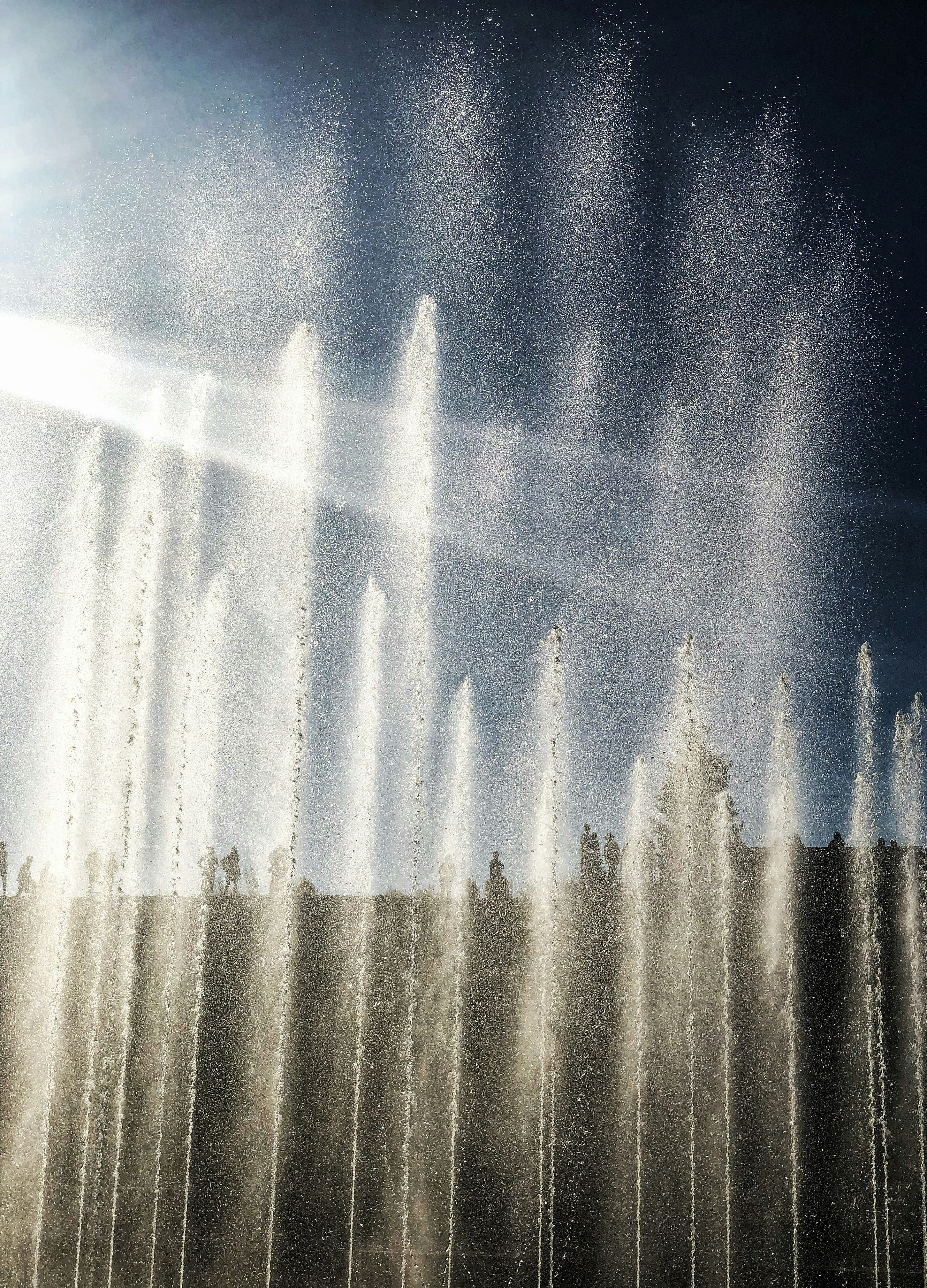 Sunlit Columns: A Fountain's Mist Reaching for the Sky