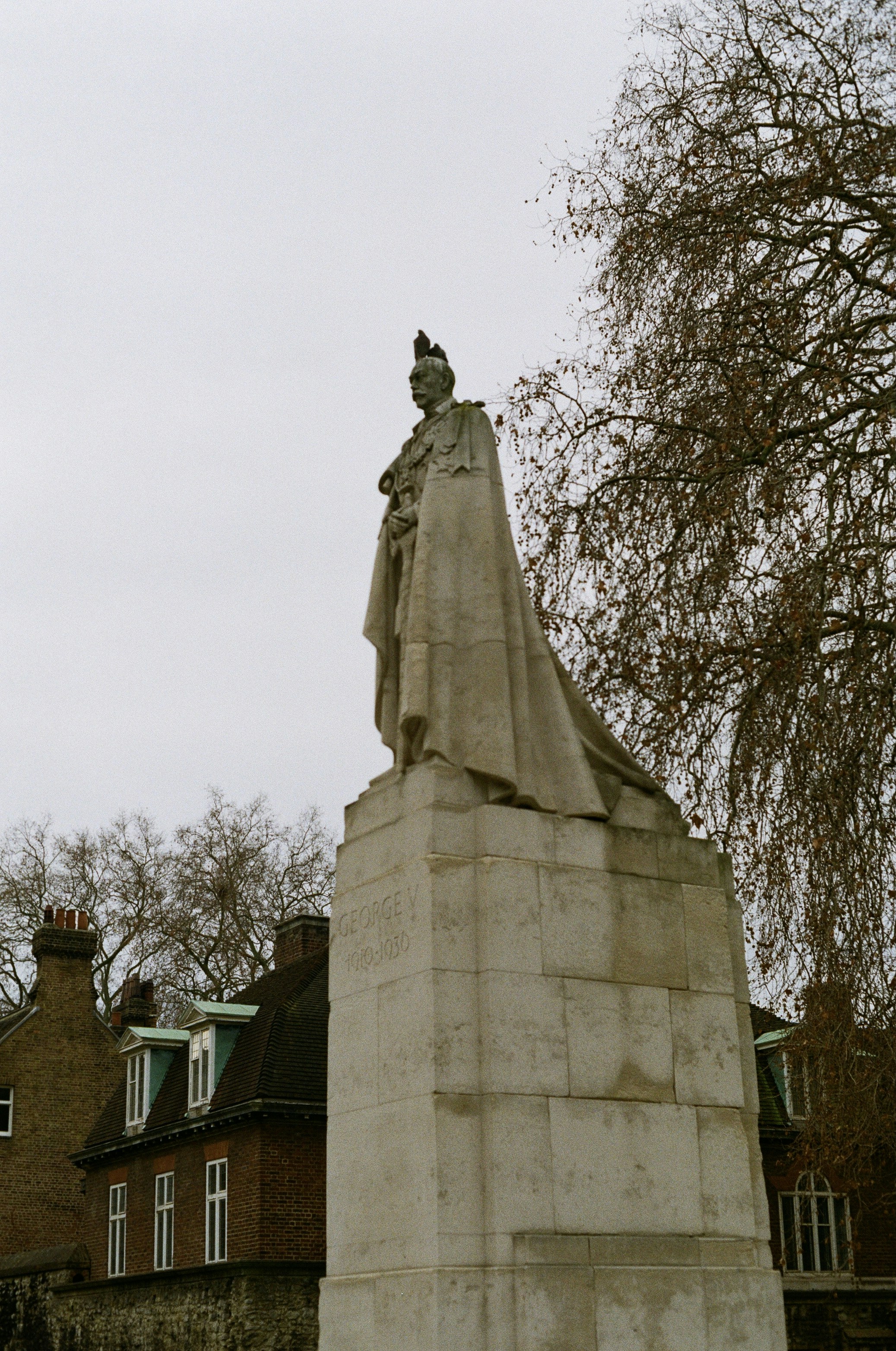 Statue of George, standing majestically atop a pedestal, surrounded by bare trees and historic architecture.