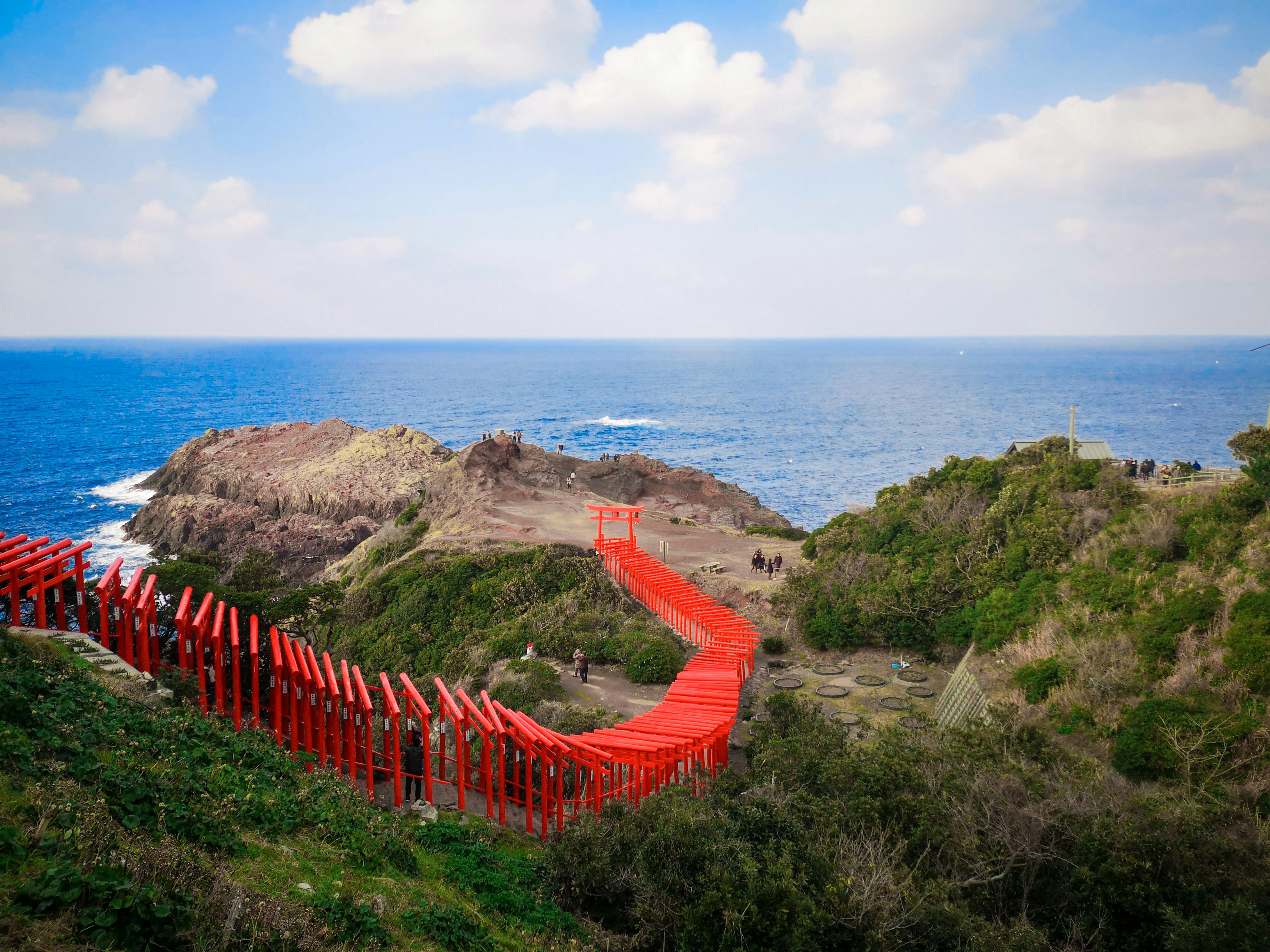 a red walkway on the side of a hill next to the ocean