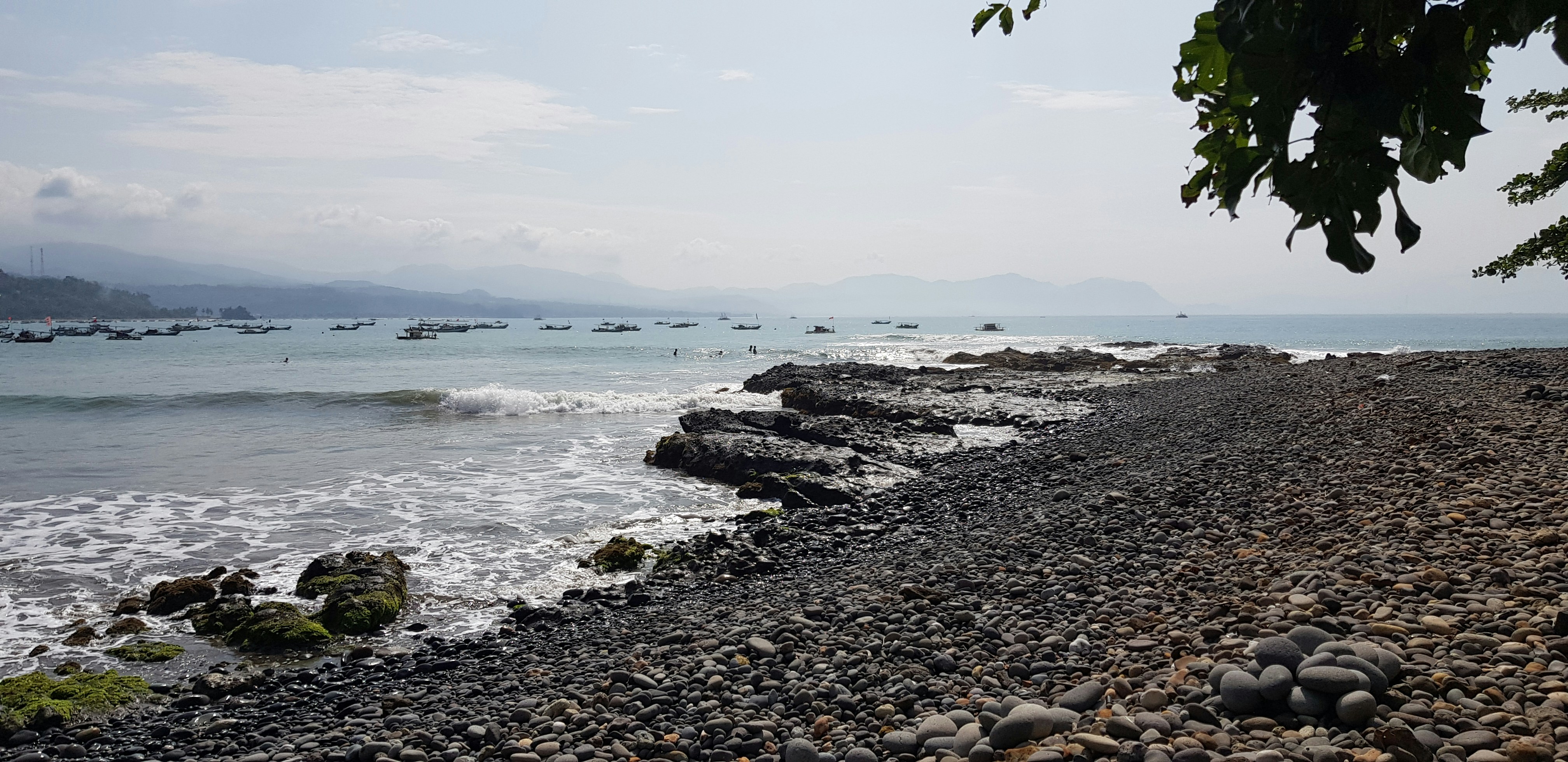 Rocky beach with gentle waves under a calm, cloudy sky.