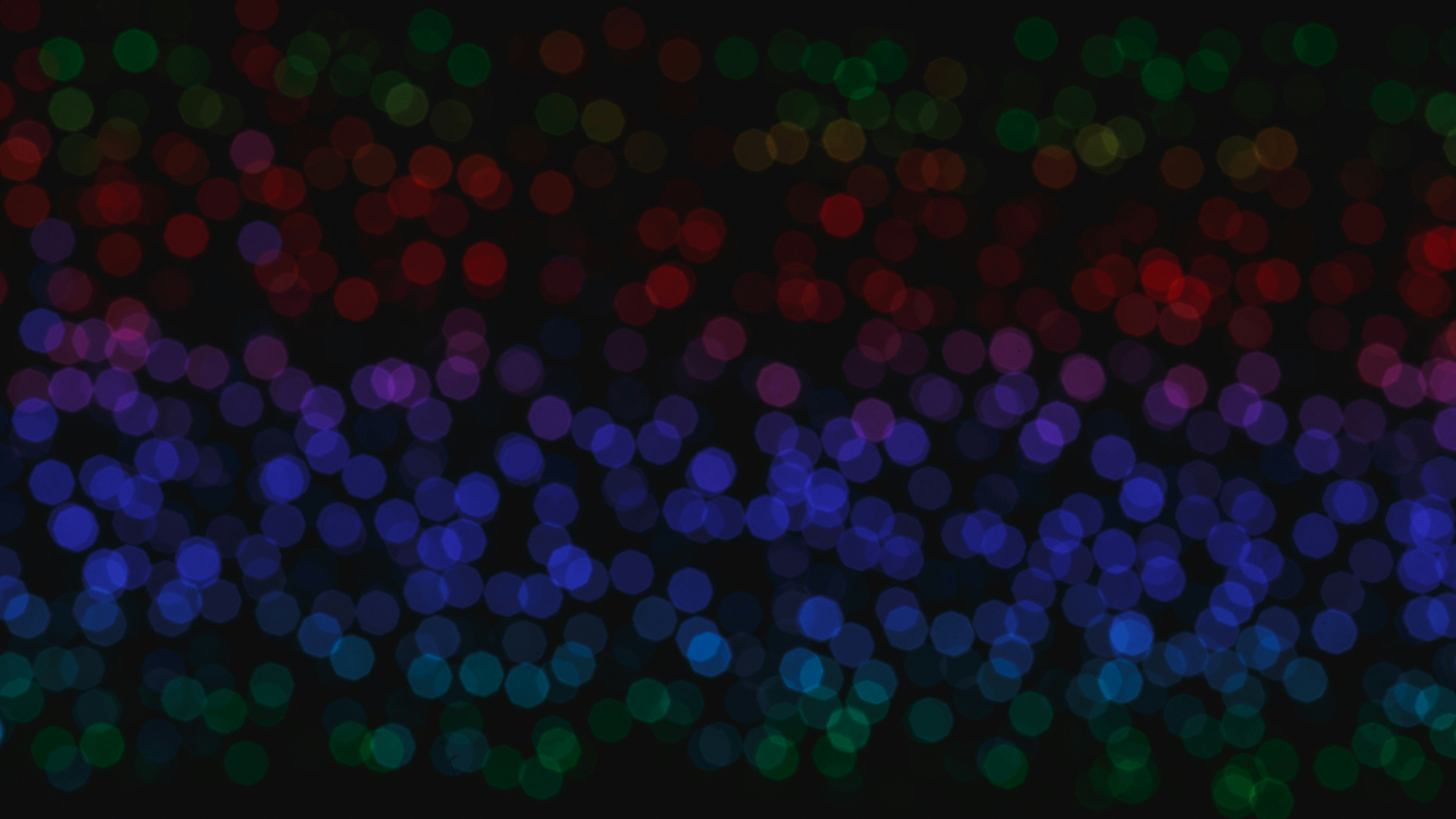 Abstract pattern of multicolored bokeh lights against a dark backdrop.