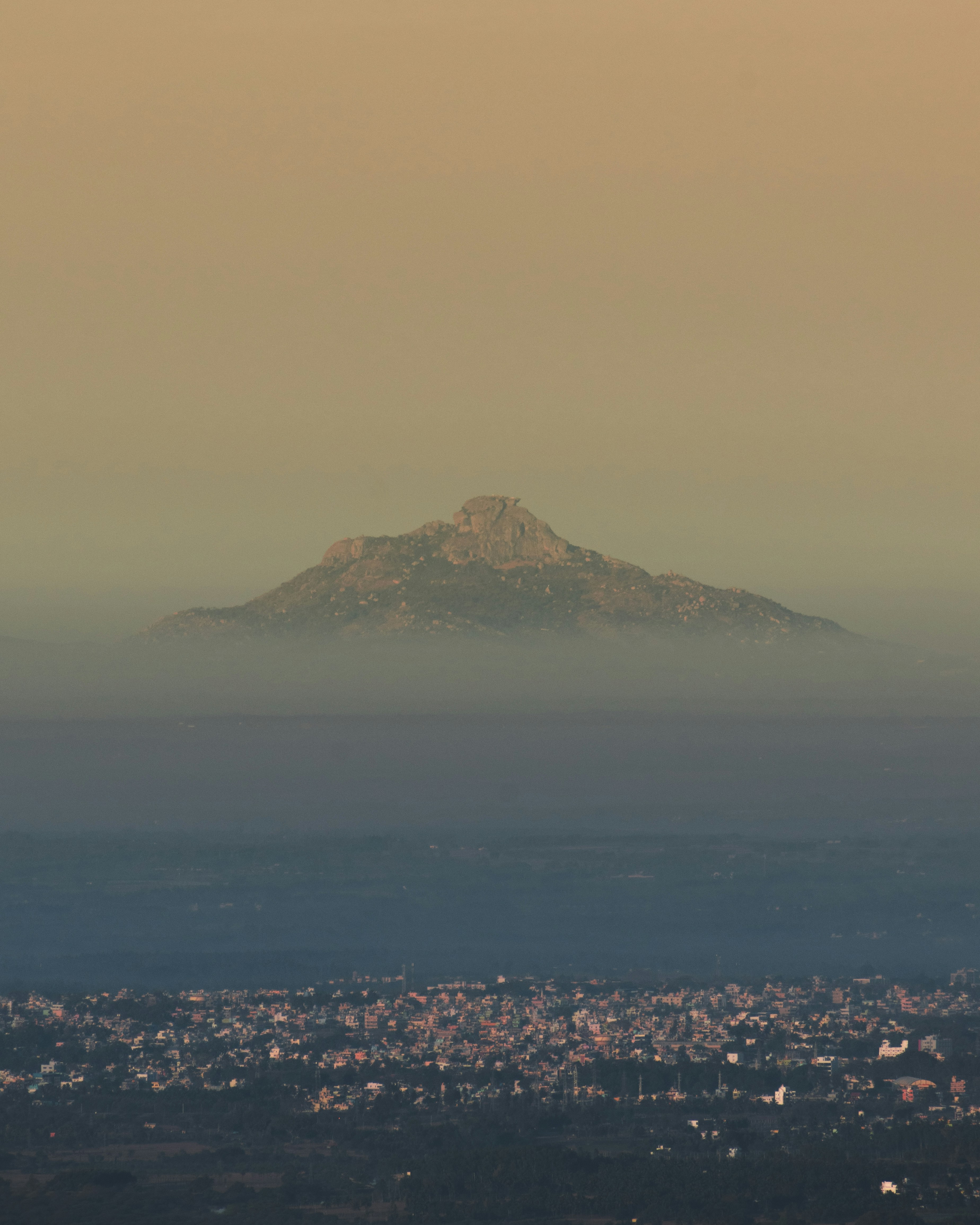 Dawn's Veil: Isolated Peak Rising from Golden Mist Over a Sleeping City
