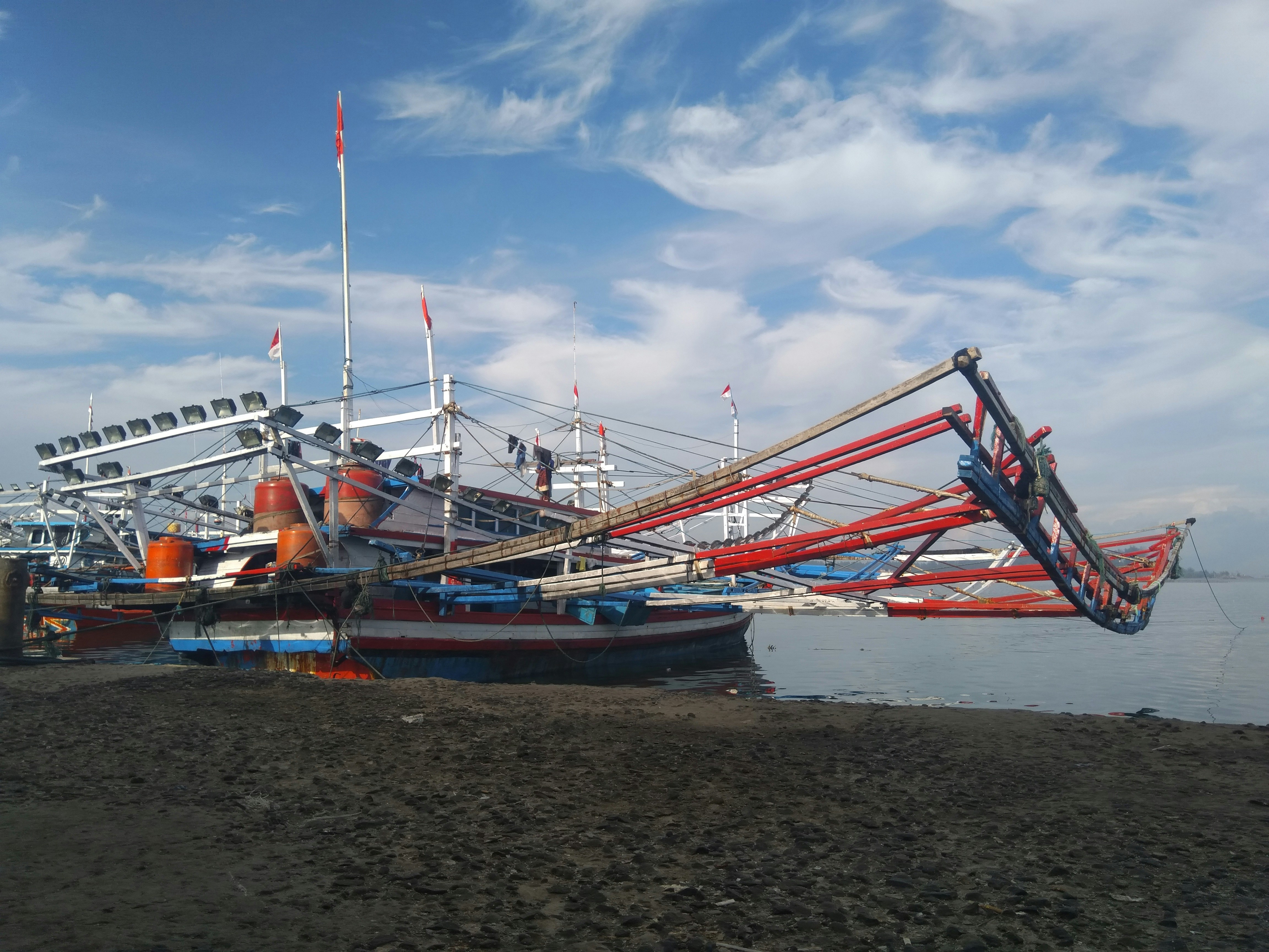 Large fishing boat resting on sandy beach under a partly cloudy sky.